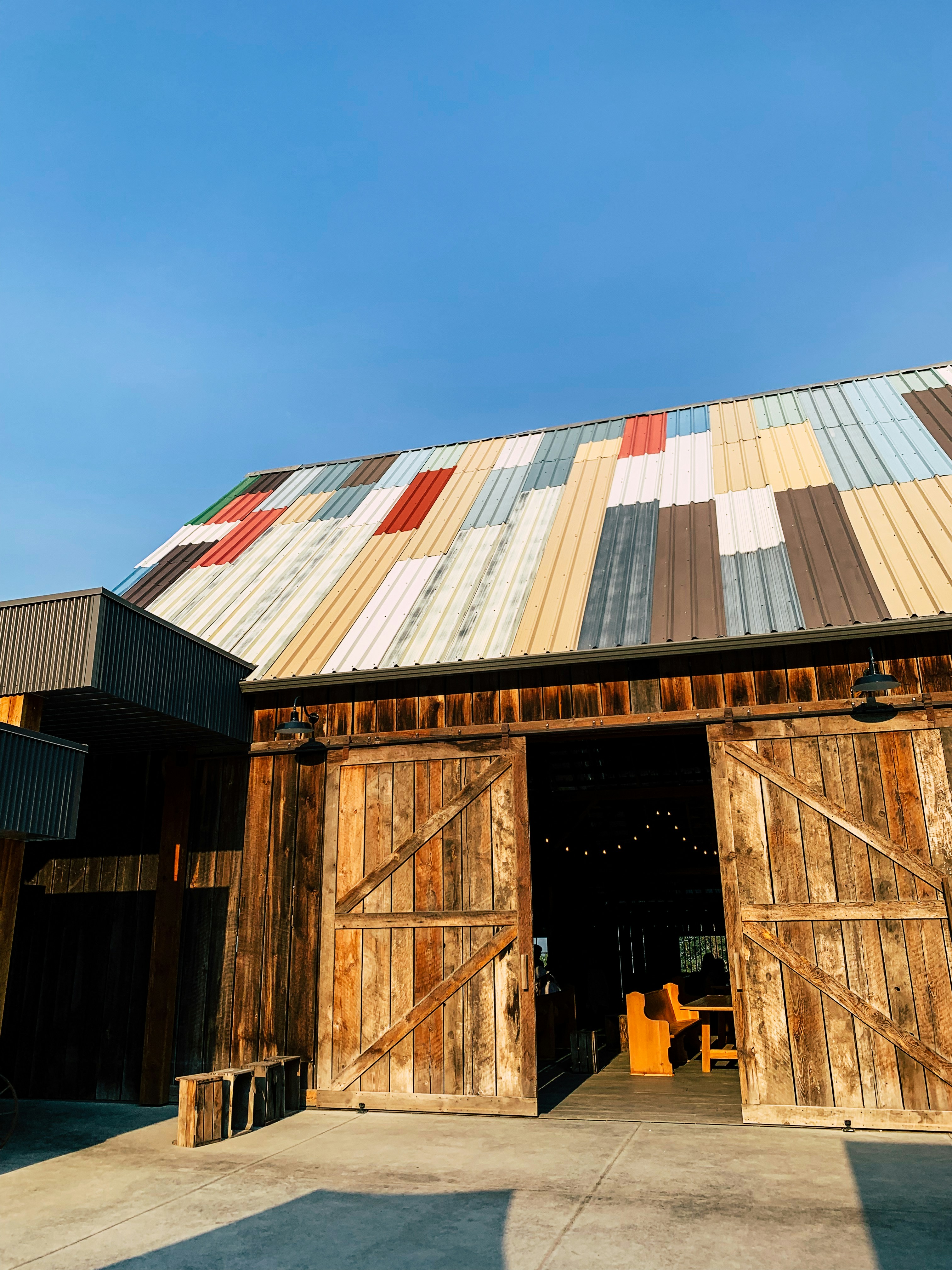 Patchwork Roof, Wooden Portal: A Rustic Industrial Barn Under a Bright Sky