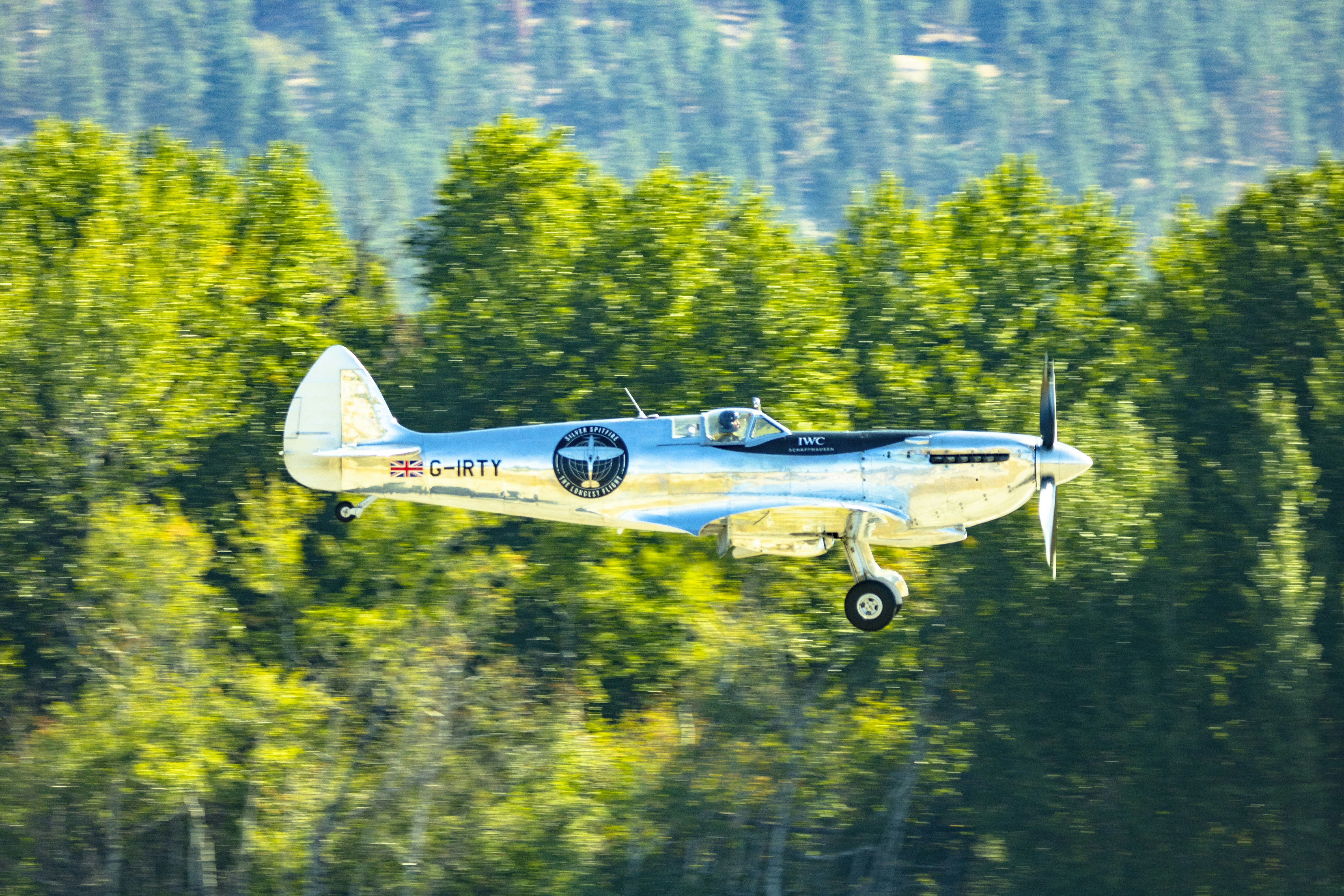 Blue and yellow jet plane flying over green trees during daytime photo ...