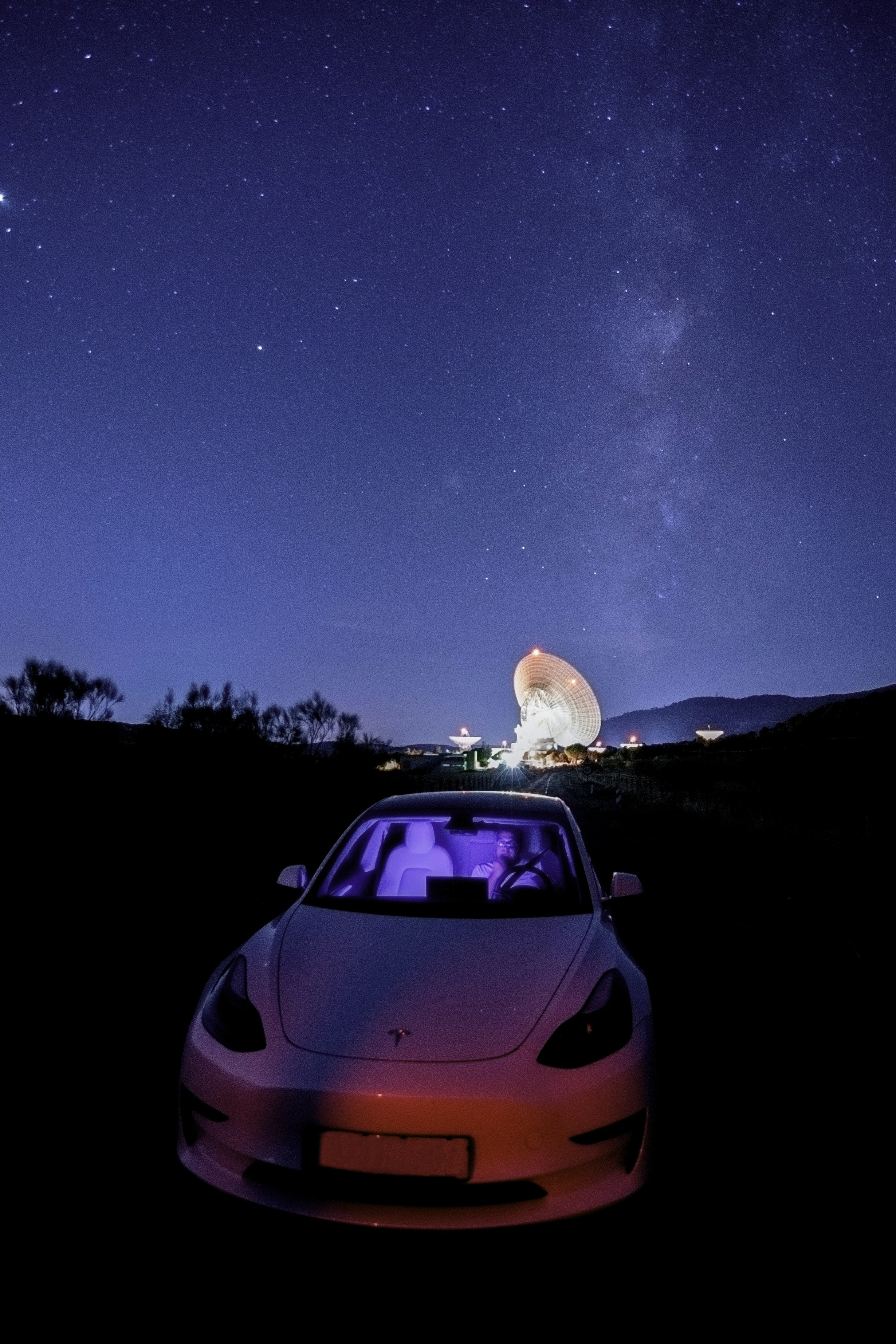 Tesla at Night: Starry Horizon Framed by a Luminous Satellite Dish