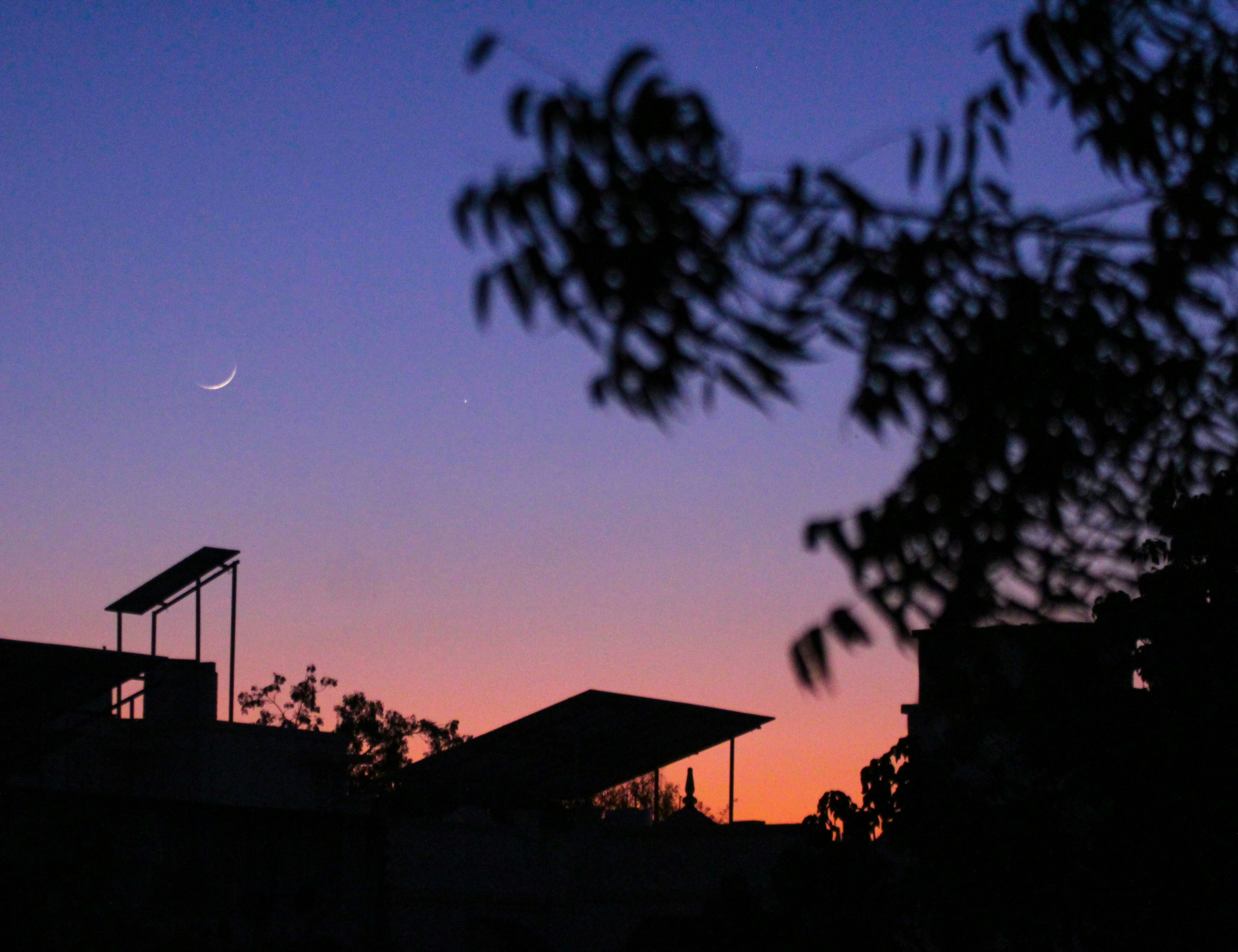 Late evening view of a building with a crescent moon in the sky