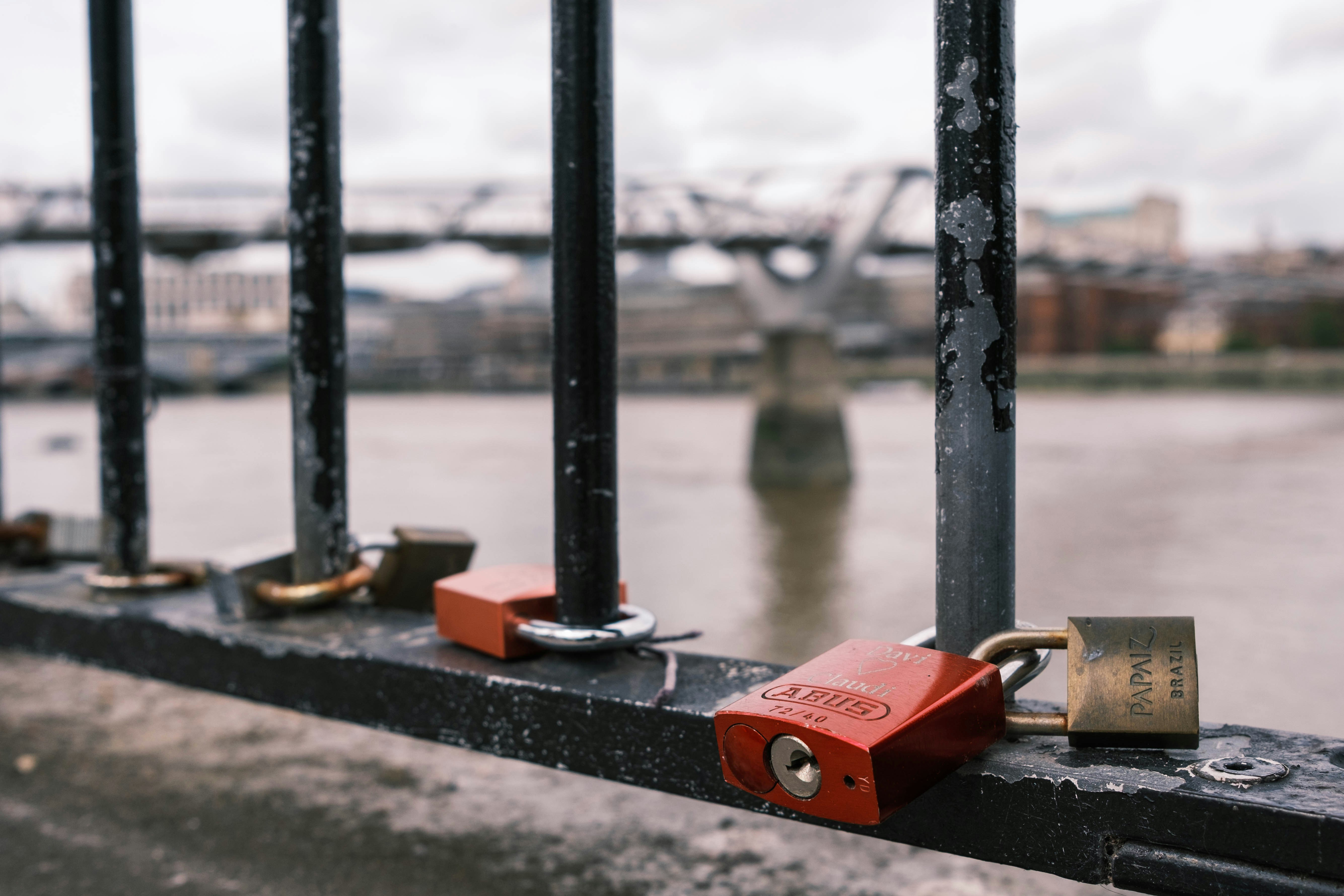 padlocks on a fence along the River Thames in front of Millennium Bridge in London