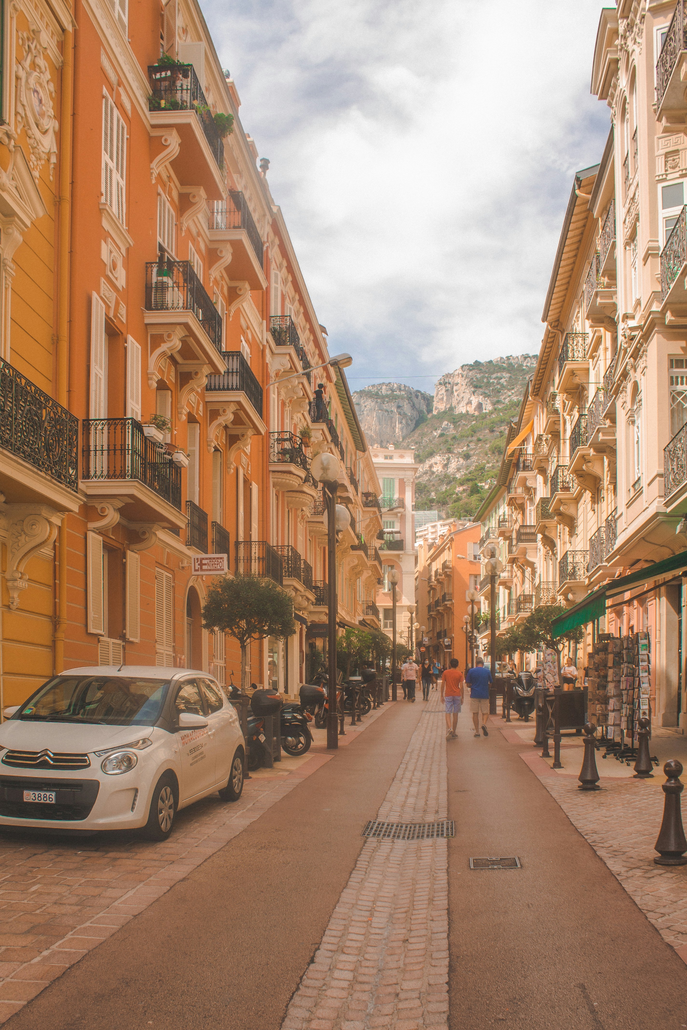 People walking on sidewalk near cars parked beside brown concrete ...