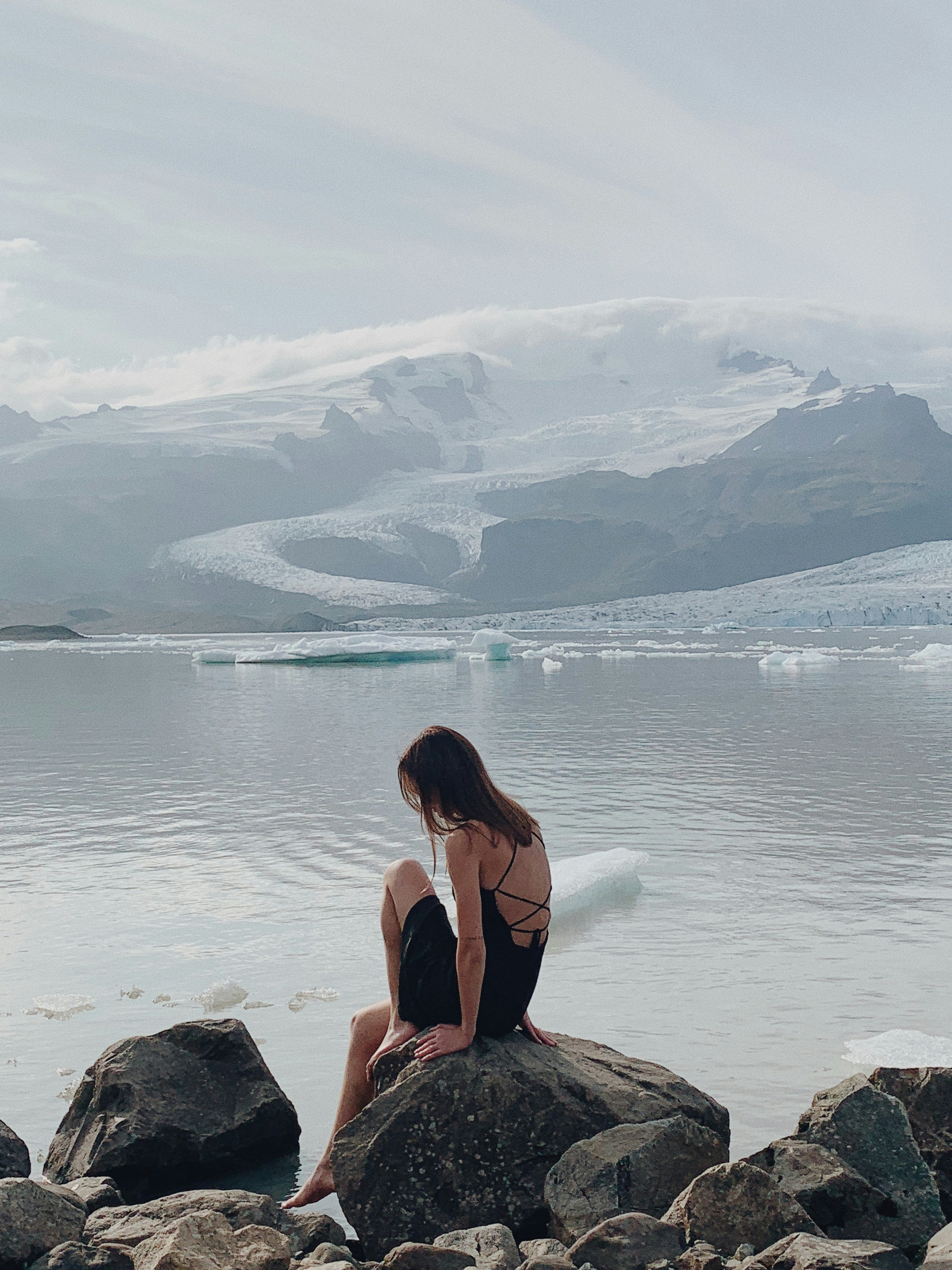 Glacial Quietude: Woman Resting on Rocks by a Glacier-fed Lake