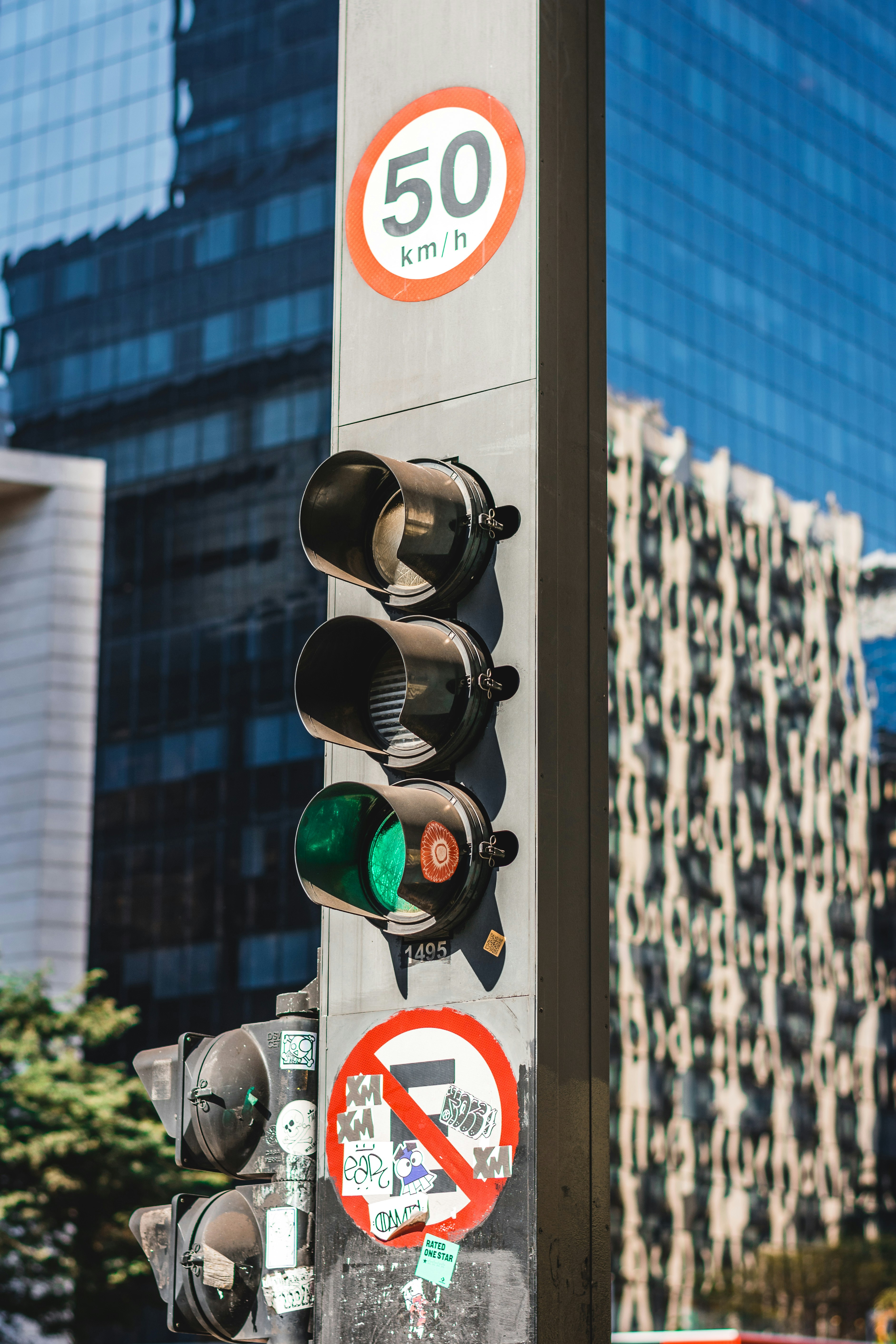 Traffic light displaying green signal against a backdrop of modern architecture and urban graffiti.