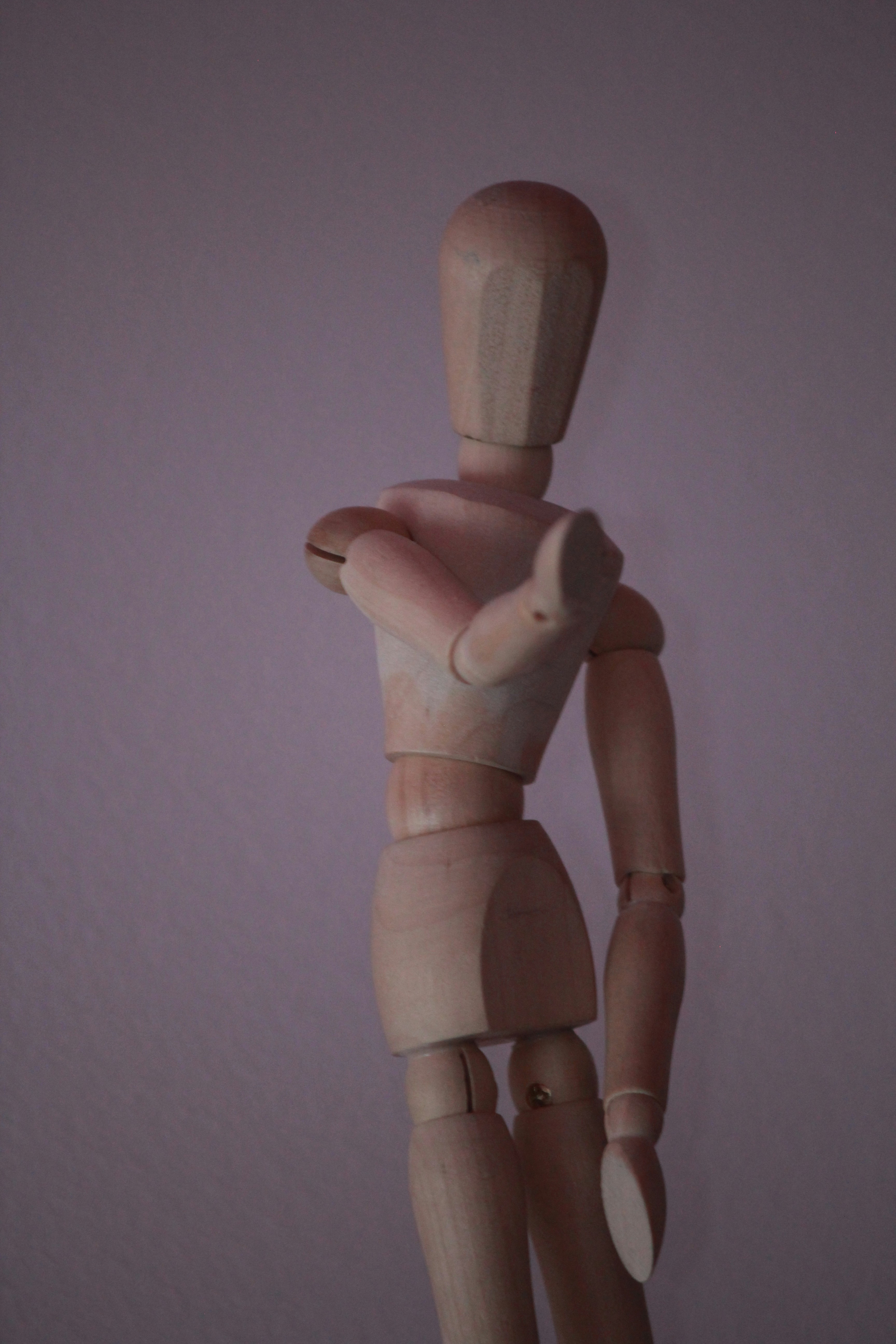Wooden mannequin striking a dynamic pose against a softly lit background.