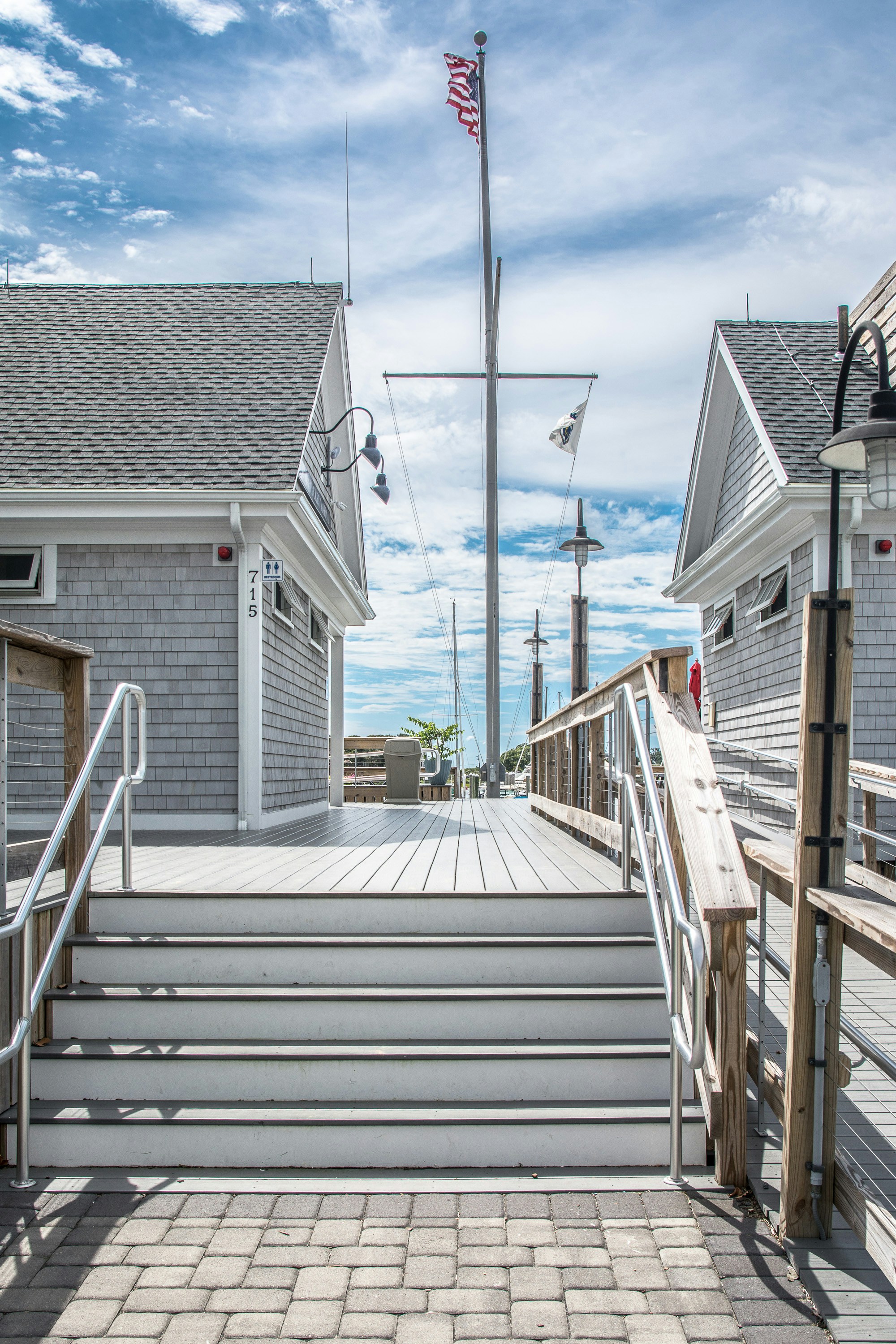 Stairs leading up to a marina with flags fluttering above, framed by charming wooden buildings. The scene captures the essence of coastal life.