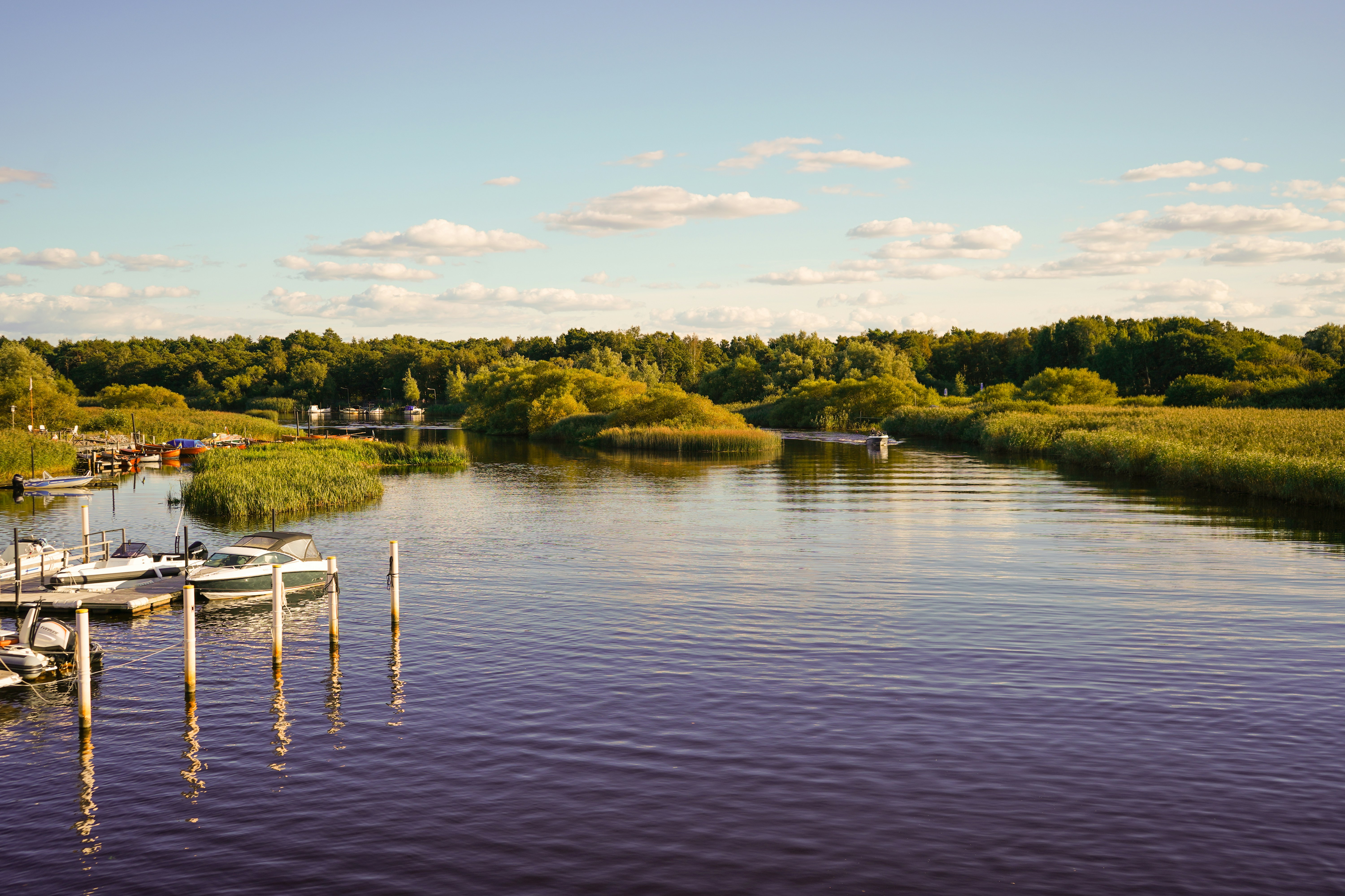 Serene landscape with boats docked along a calm river under a clear sky.