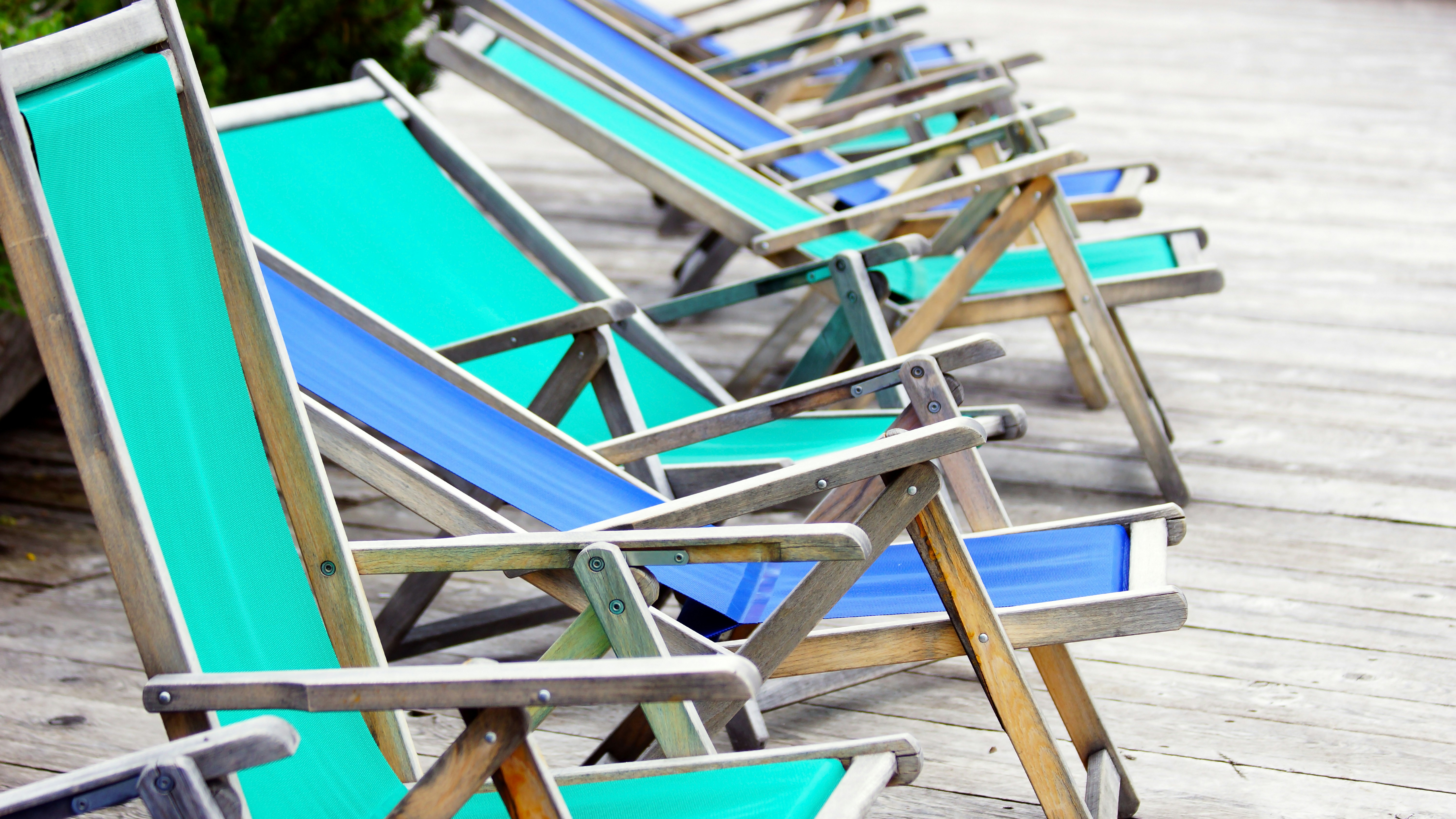 Diagonal Parade of Colorful Deck Chairs Along a Weathered Boardwalk