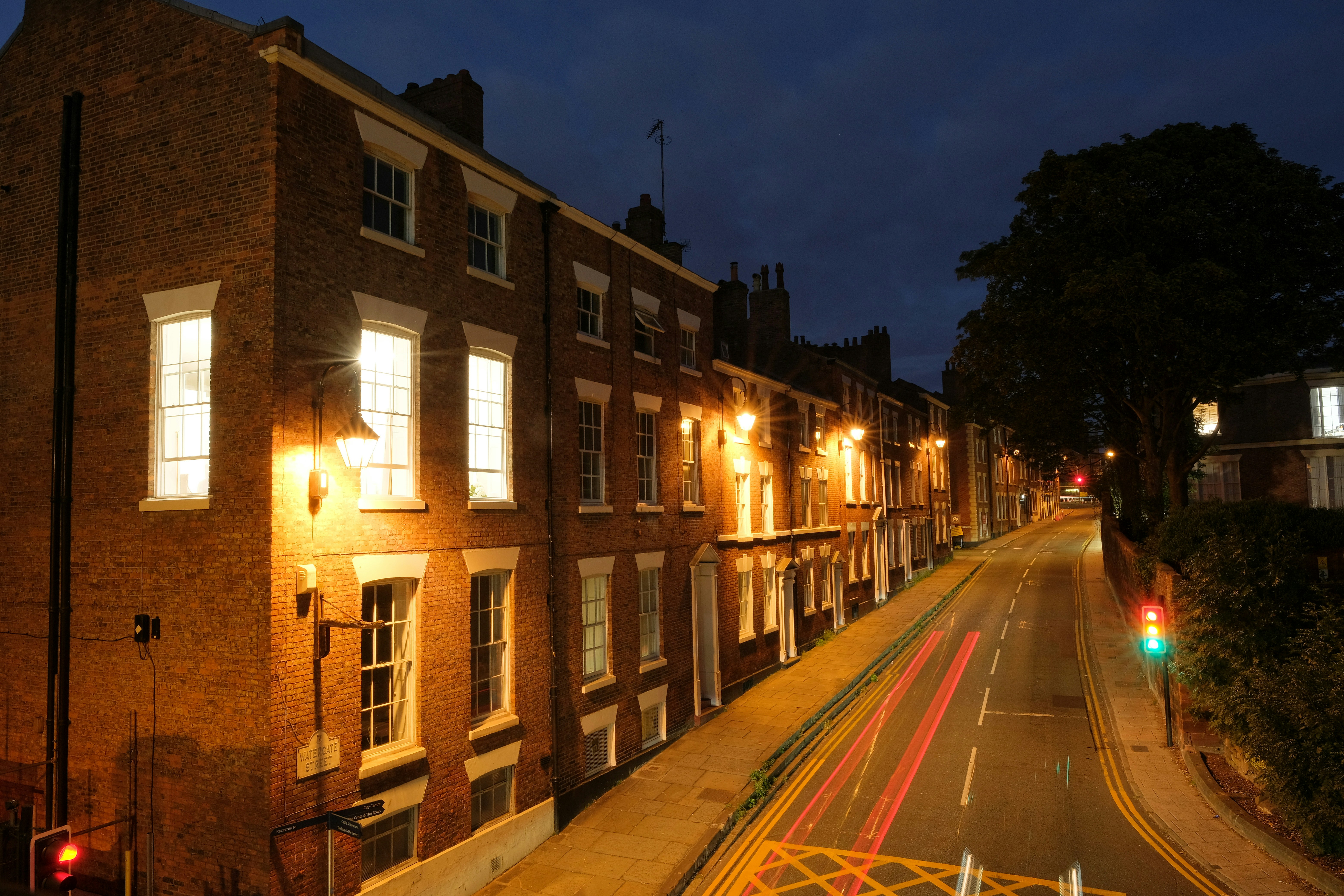 Blue-hour Rows: Brick Facades and Red Light Trails