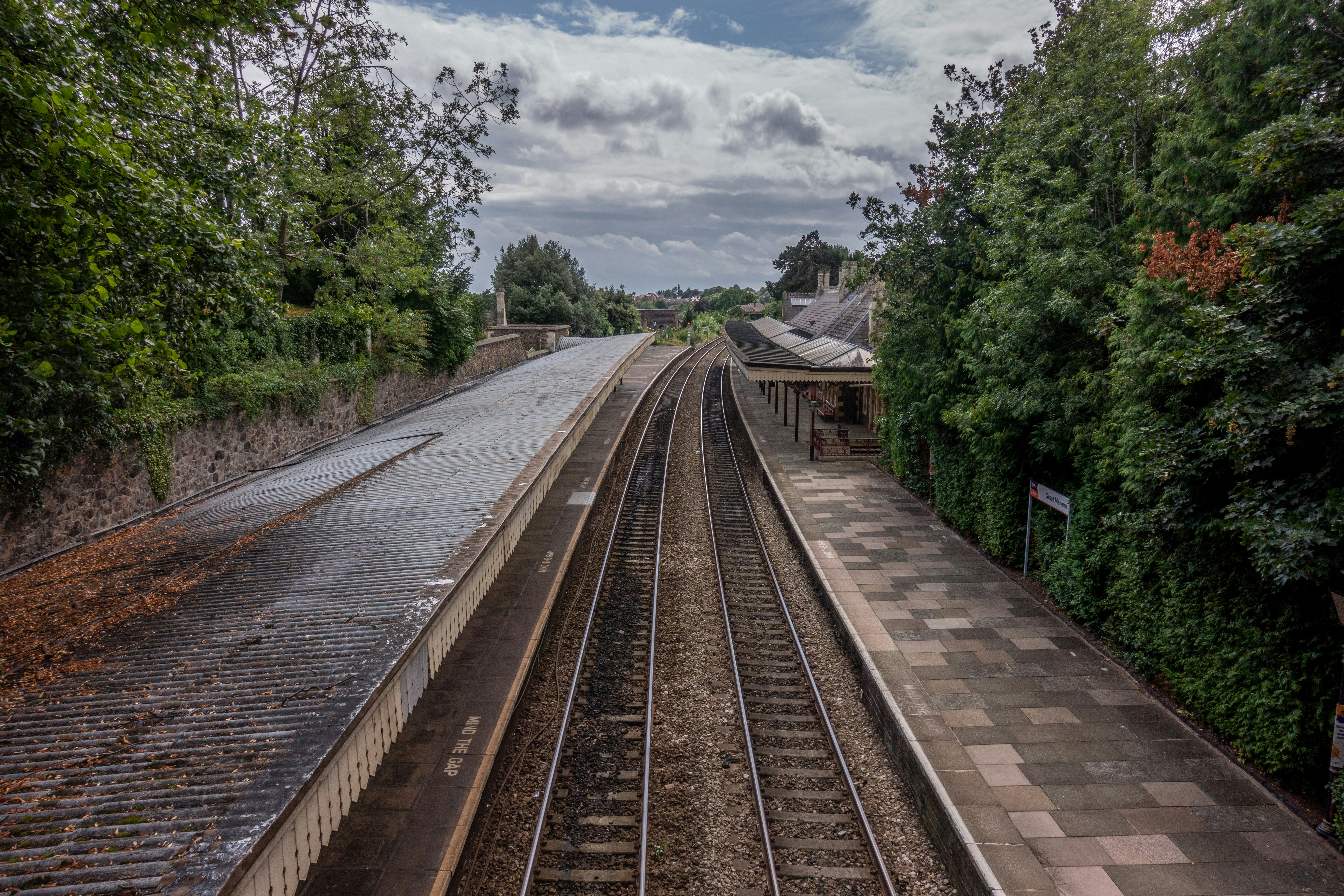 train rail under cloudy sky during daytime