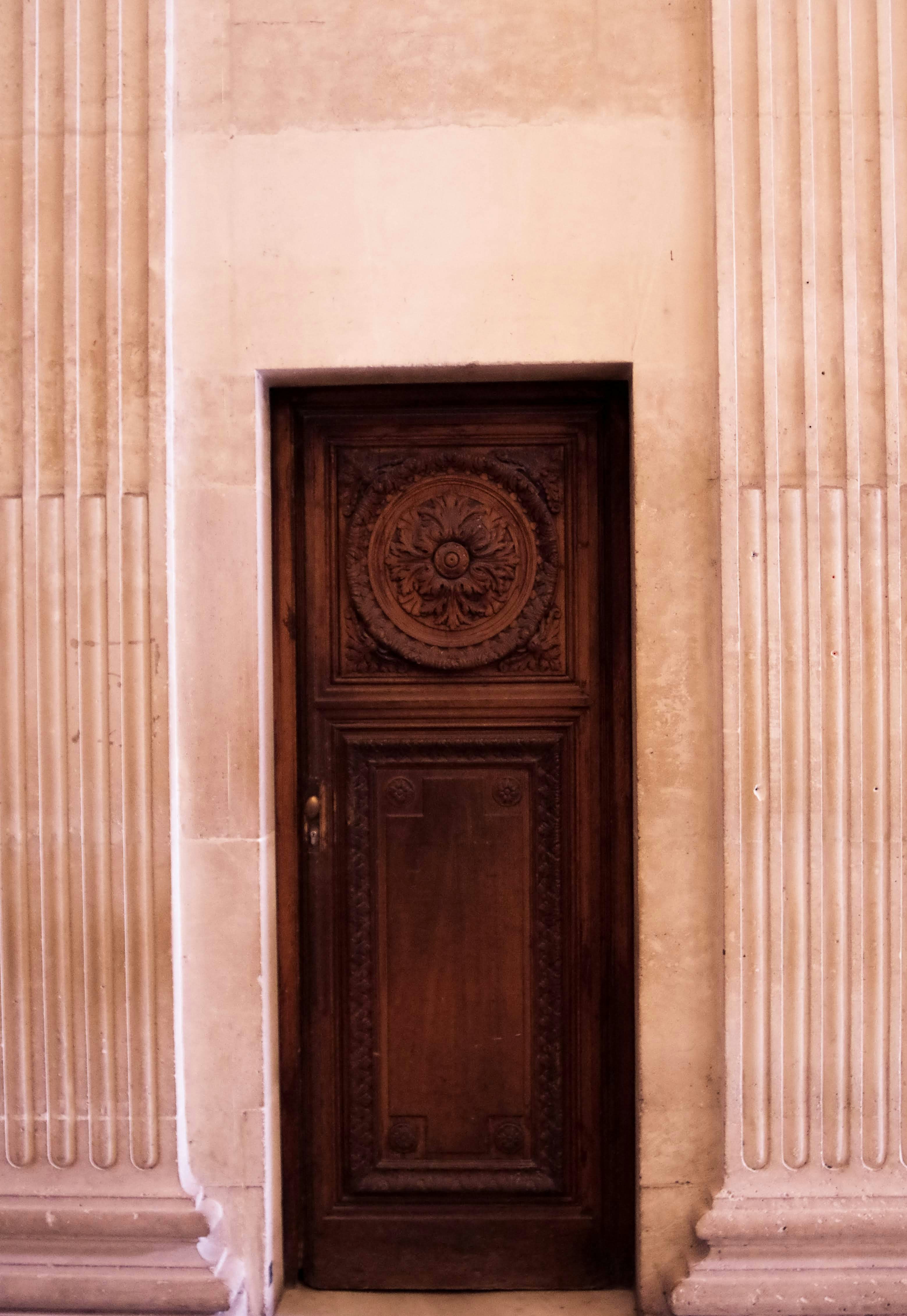 Intricately carved wooden door framed by elegant stone columns, hinting at the stories beyond its threshold.