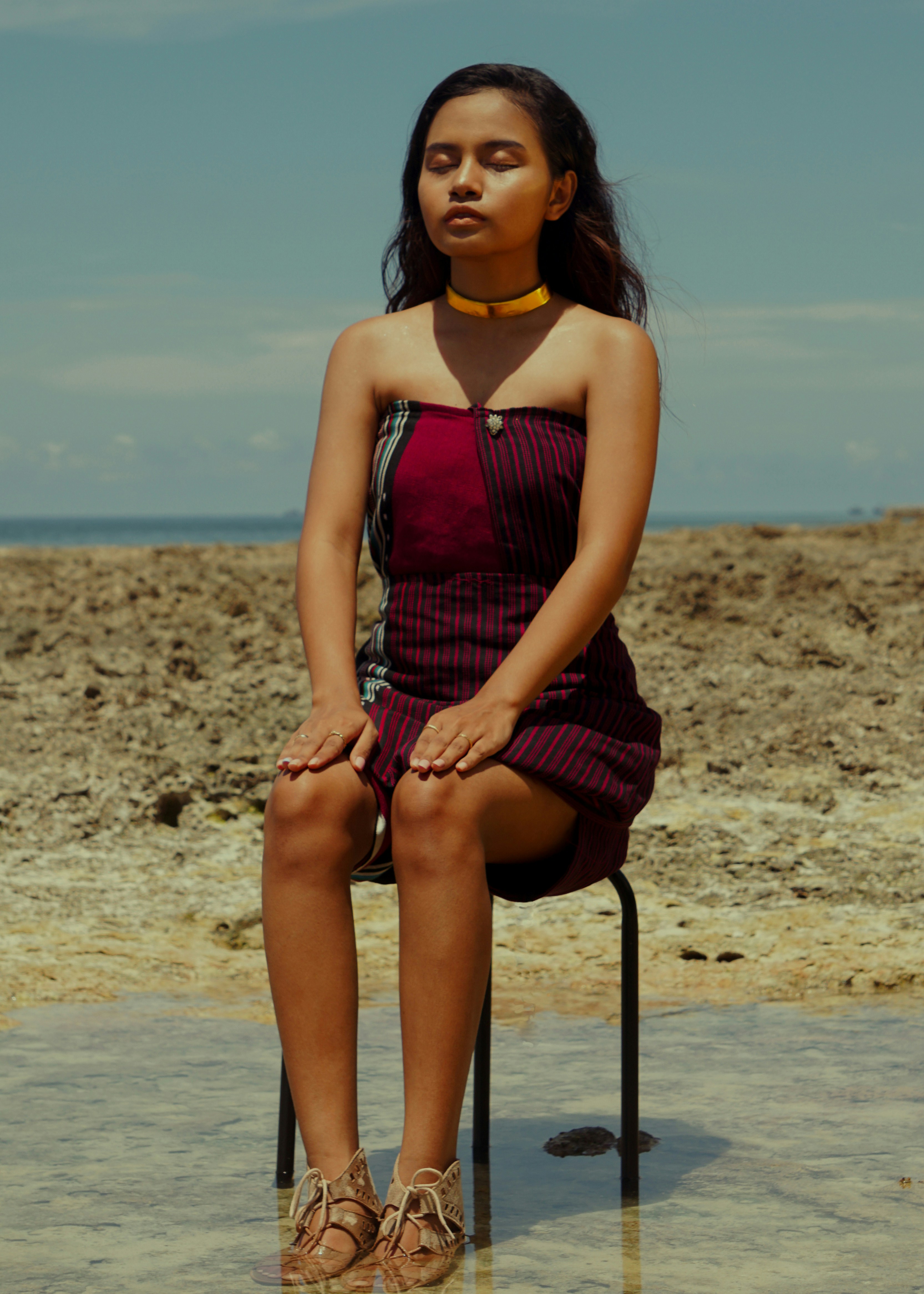 Woman in black and red sleeveless dress sitting on chair on beach ...