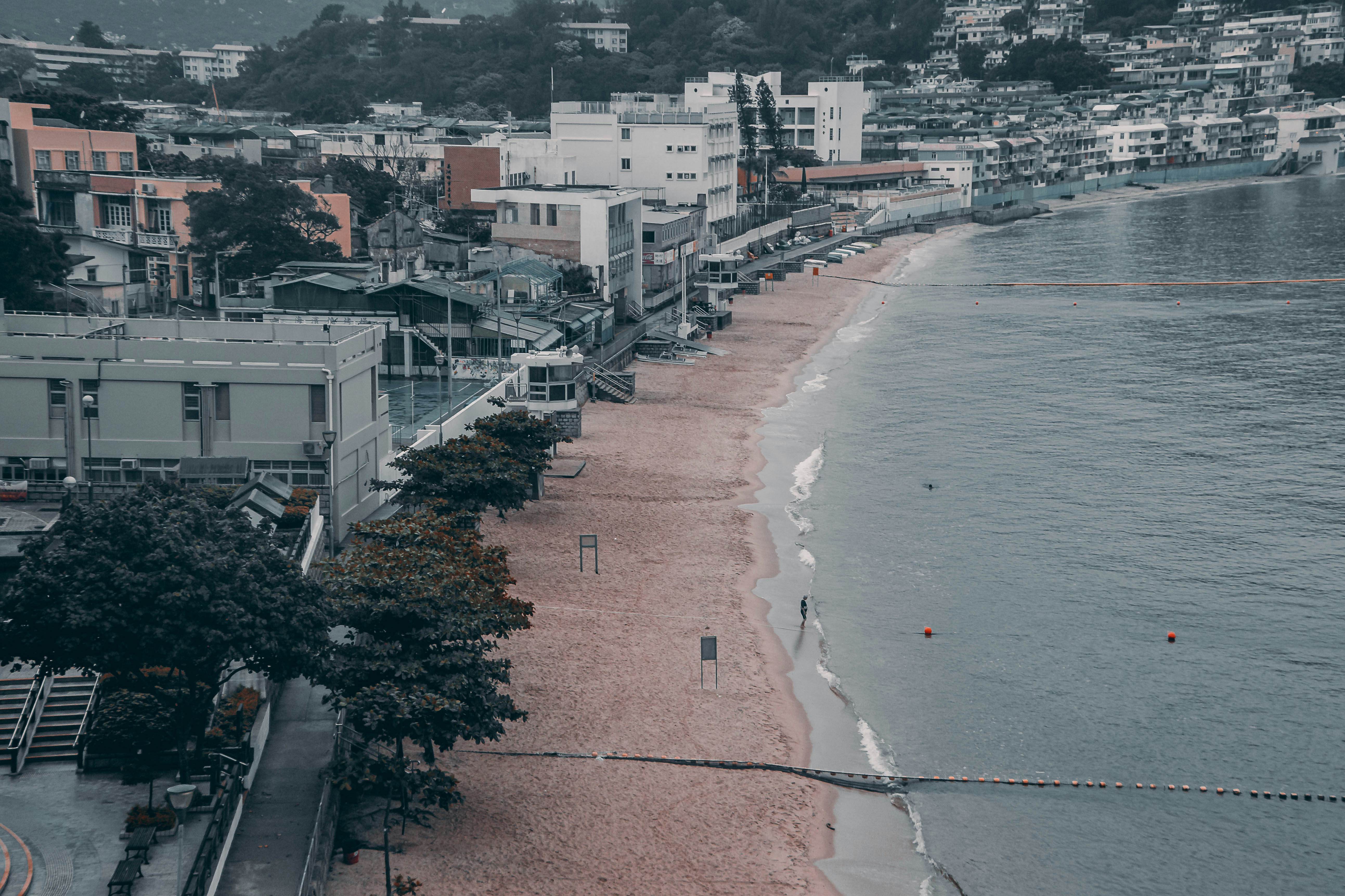 A tranquil beach scene showcasing a stretch of sand bordered by urban structures, with gentle waves lapping at the shore.