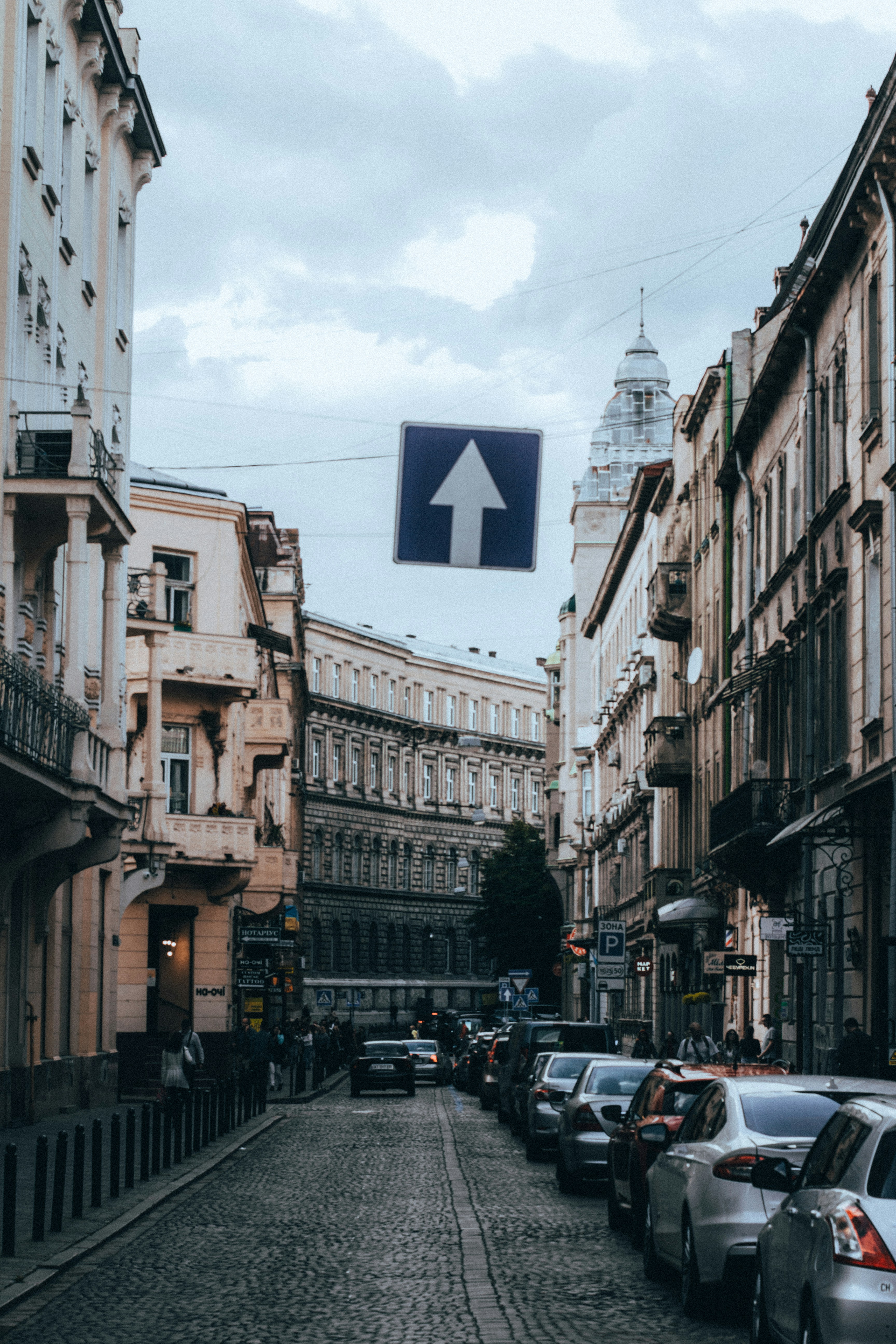 Cars parked on side of the road in between buildings during daytime ...