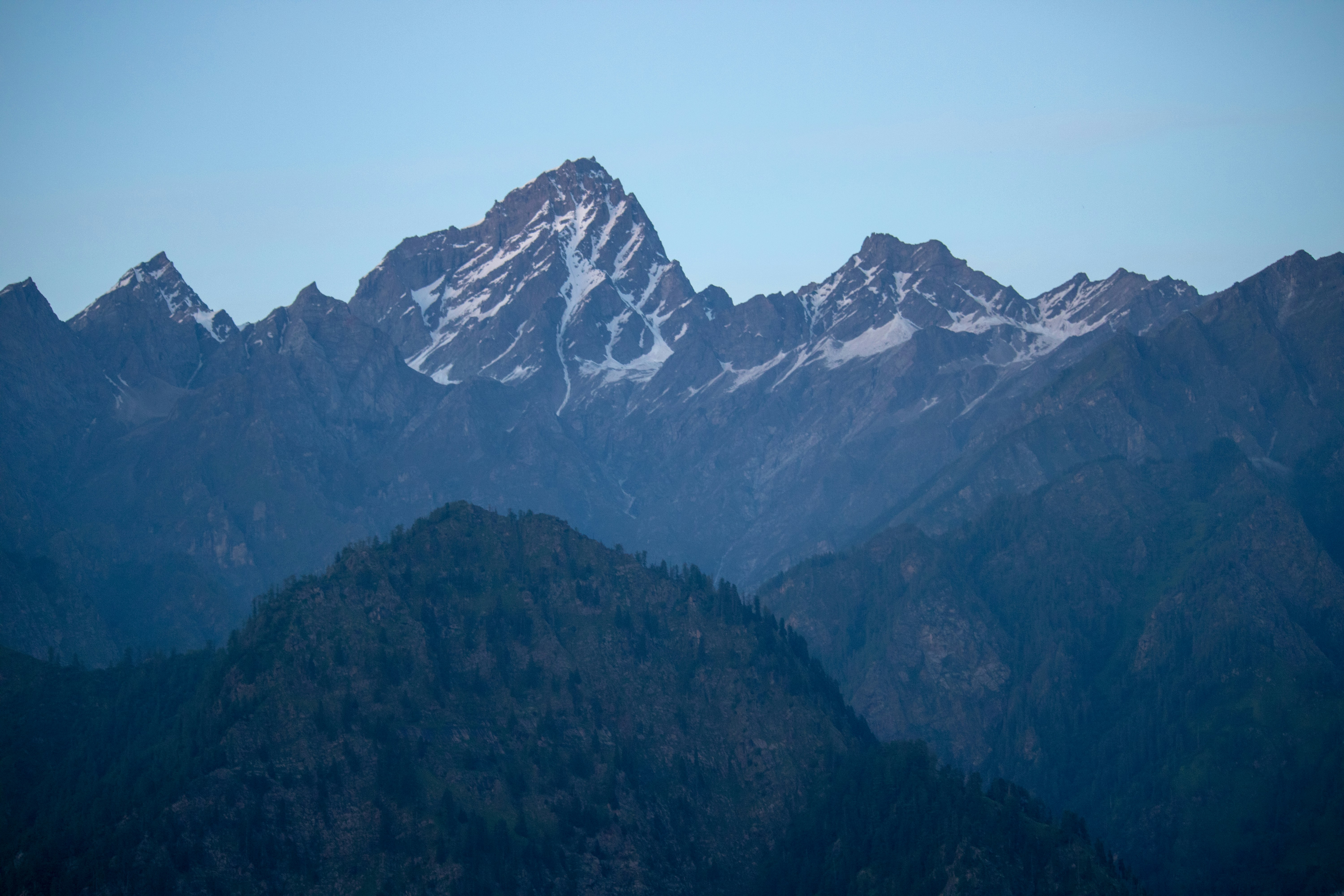 Dramatic mountain range under a twilight sky, showcasing rugged peaks and subtle snow caps.