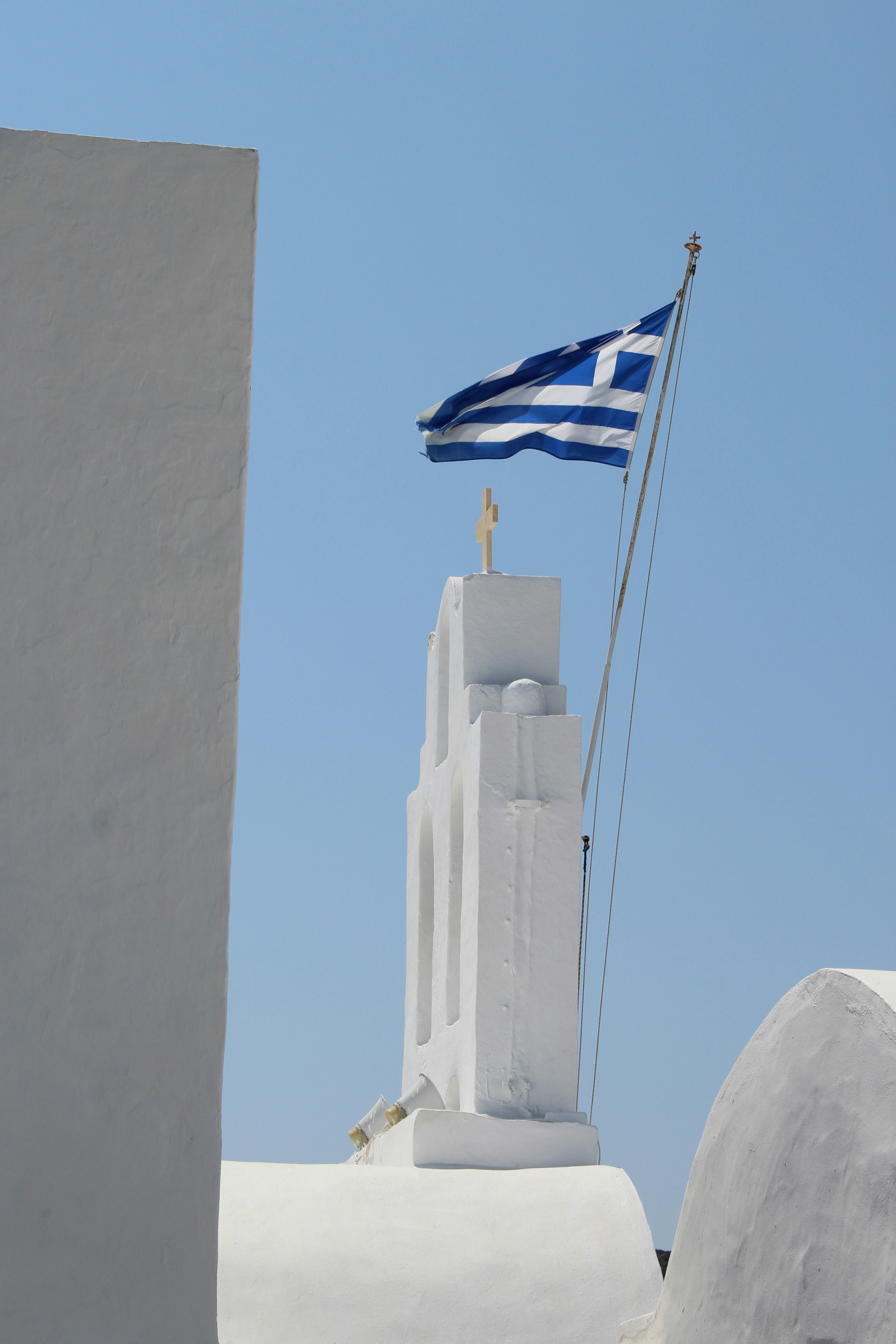 Flag Atop a White Cycladic Tower Beneath a Clear Aegean Sky