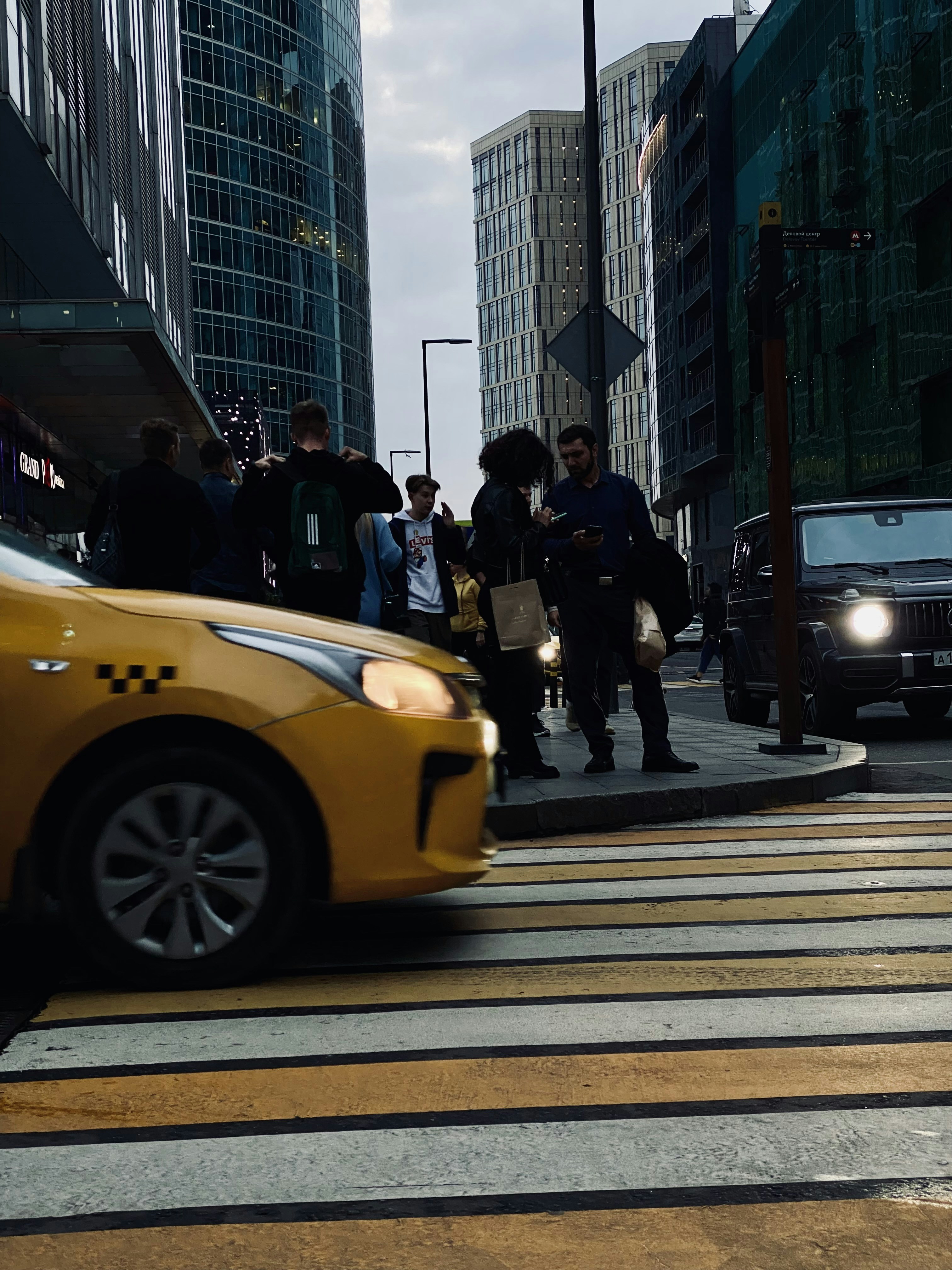 A taxi cab driving down a street next to tall buildings photo – Free ...