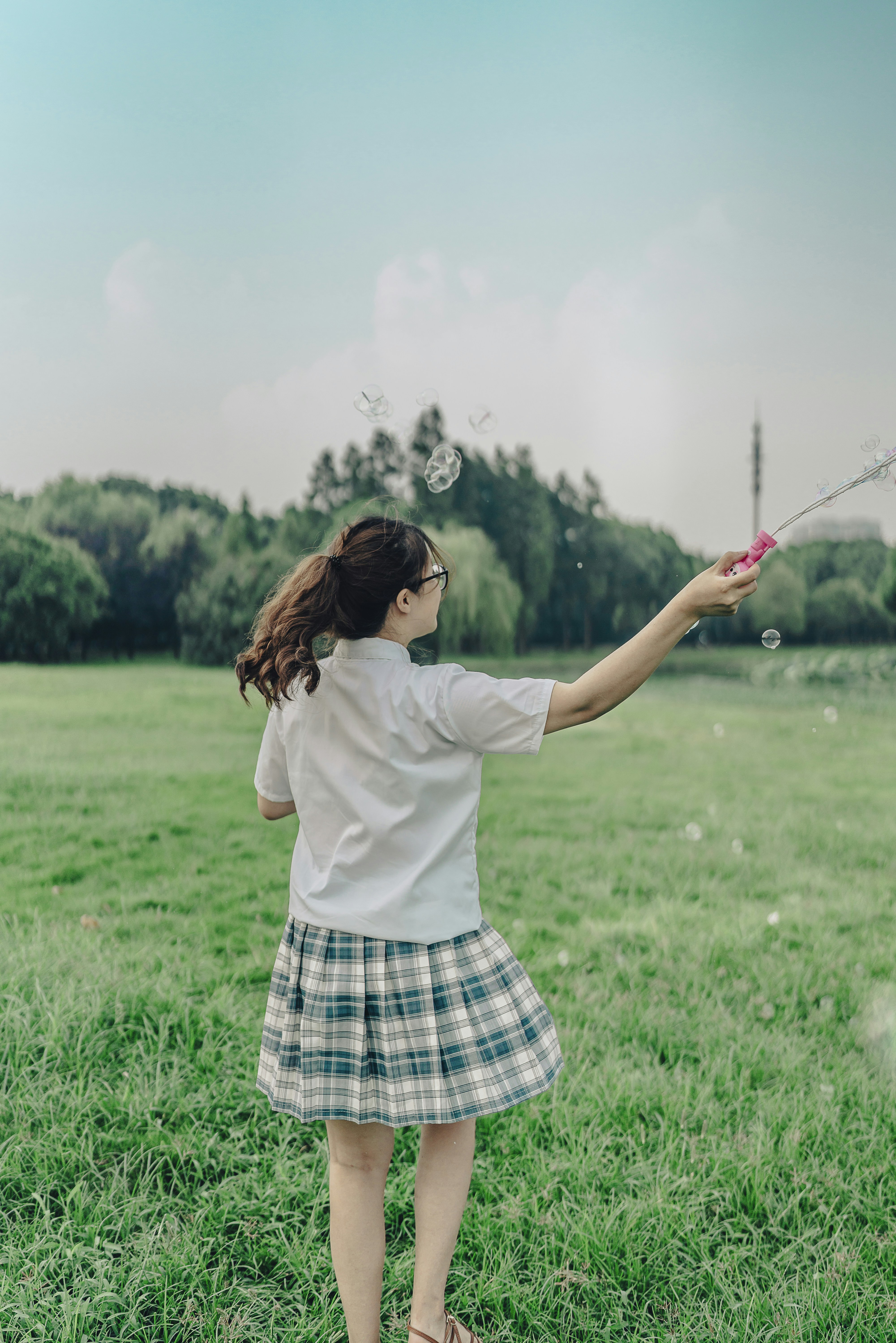 Playful spray: a girl tugs bubbles across sunlit meadow