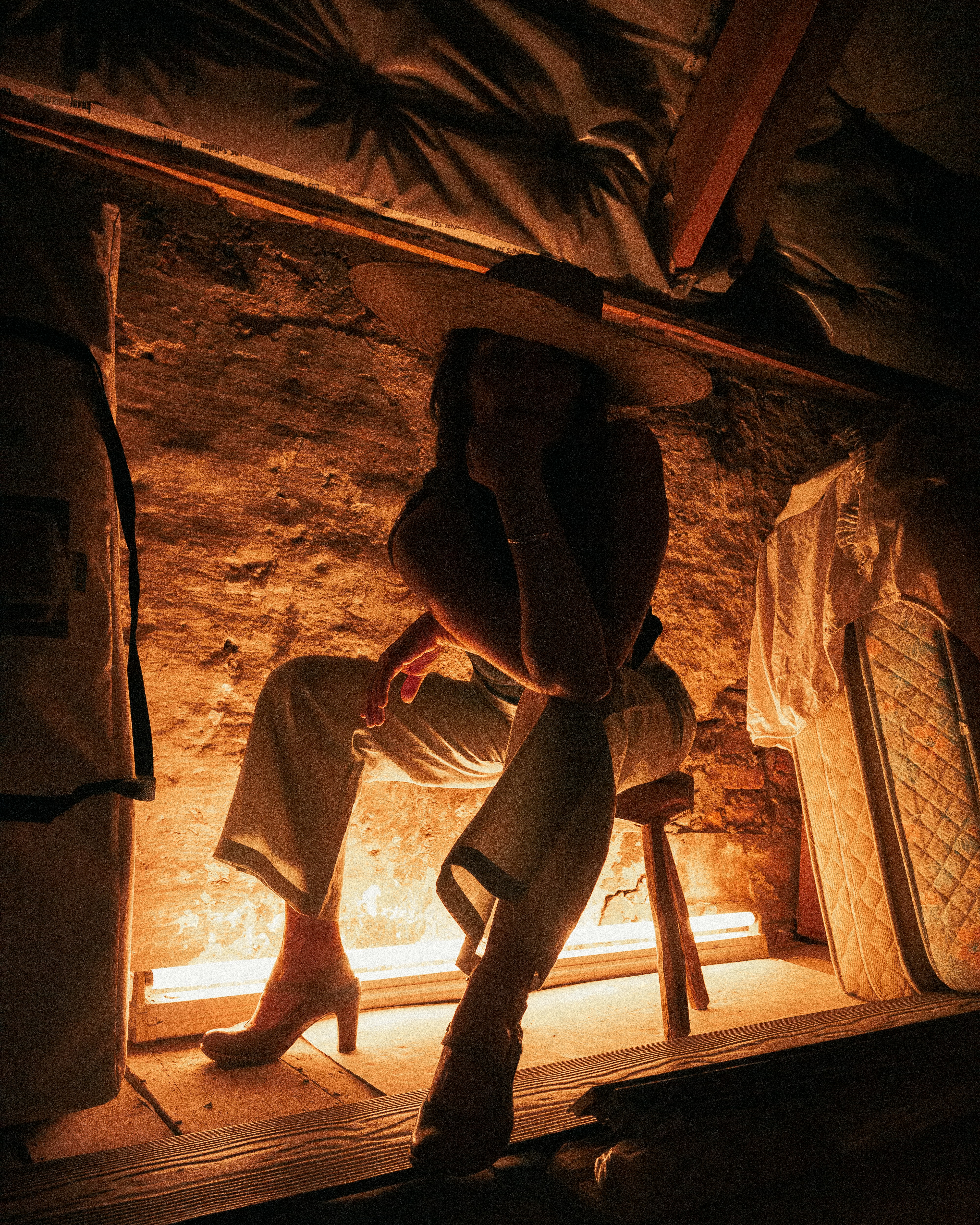 Amber Glow Silhouette: A Quiet Moment Beneath a Straw Hat in a Rustic Loft