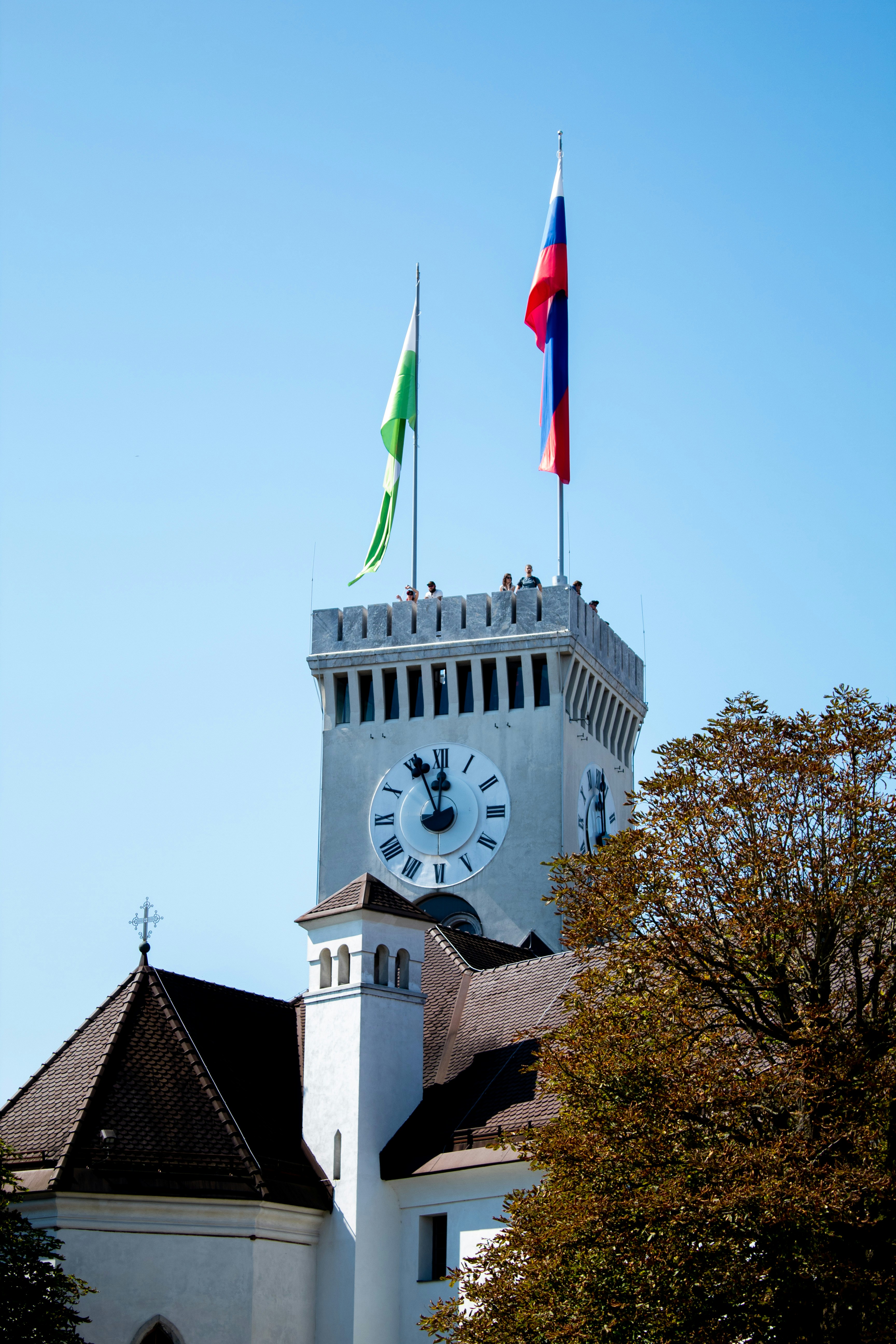 A clock tower with two flags on top of it photo – Free Ljubljana castle ...