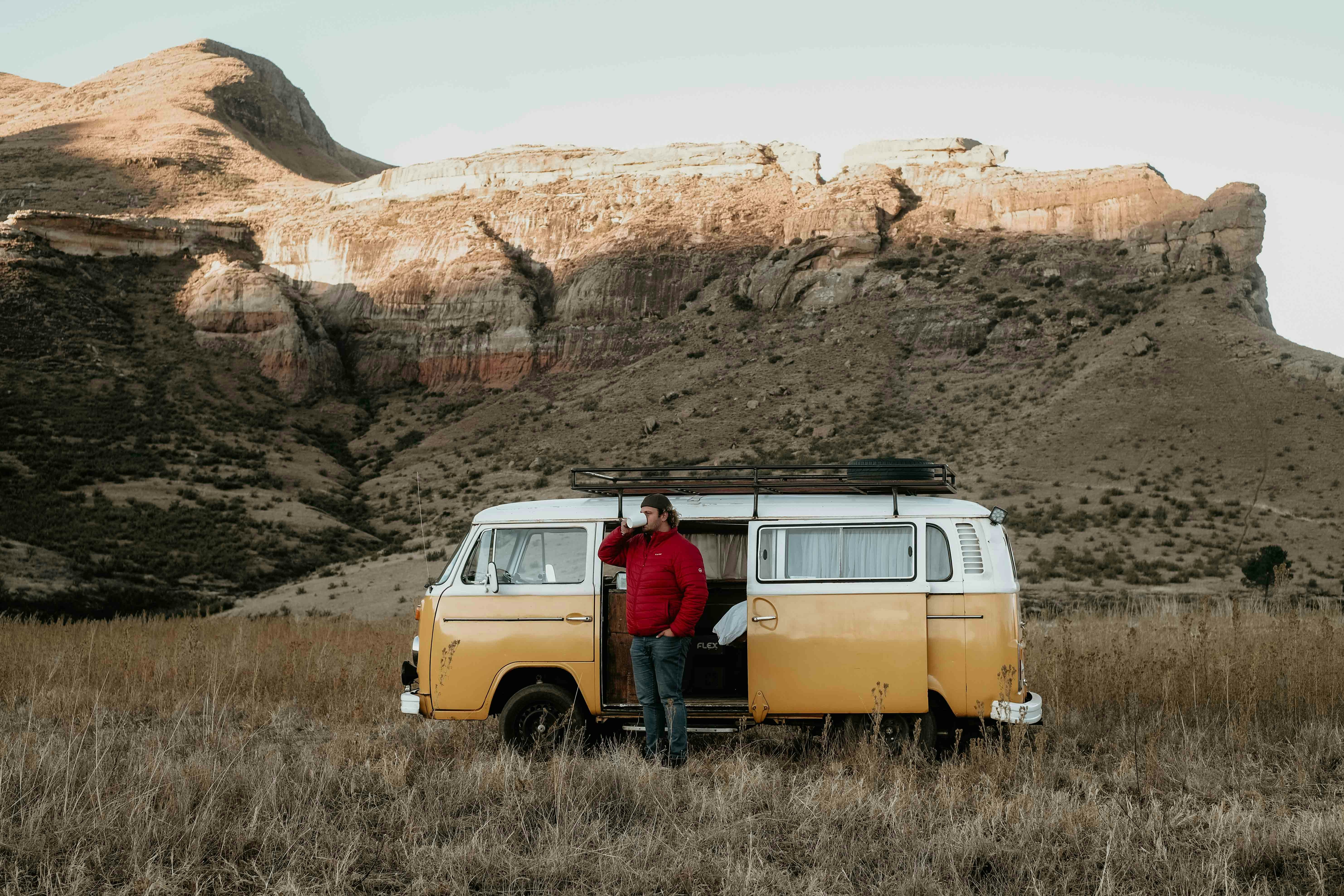 Across the Plain: A Red Jacket Stands by a Classic Camper