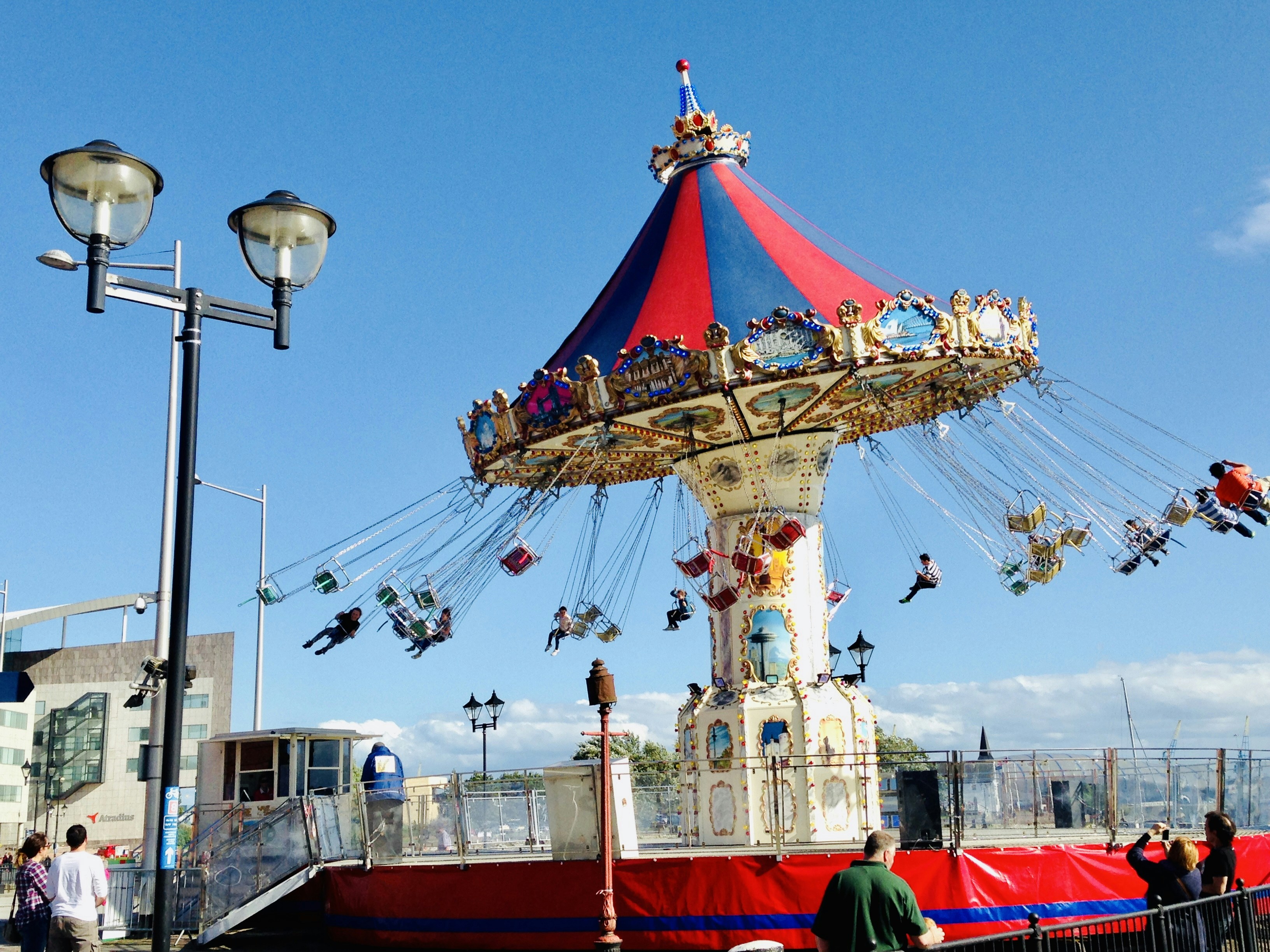 Colorful carousel with swinging seats in motion, surrounded by a lively atmosphere and clear blue sky.