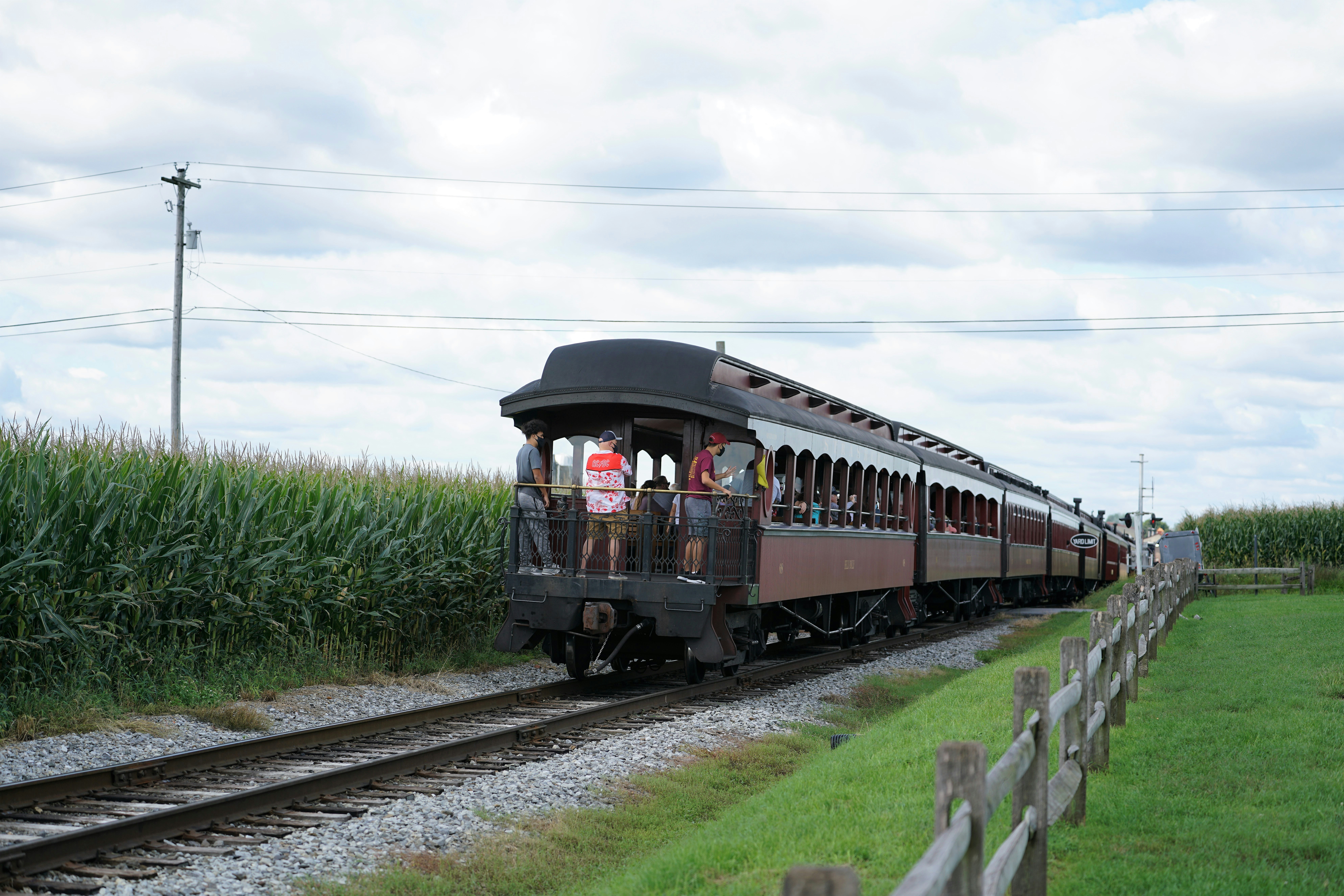 A train traveling down train tracks next to a corn field photo – Free ...