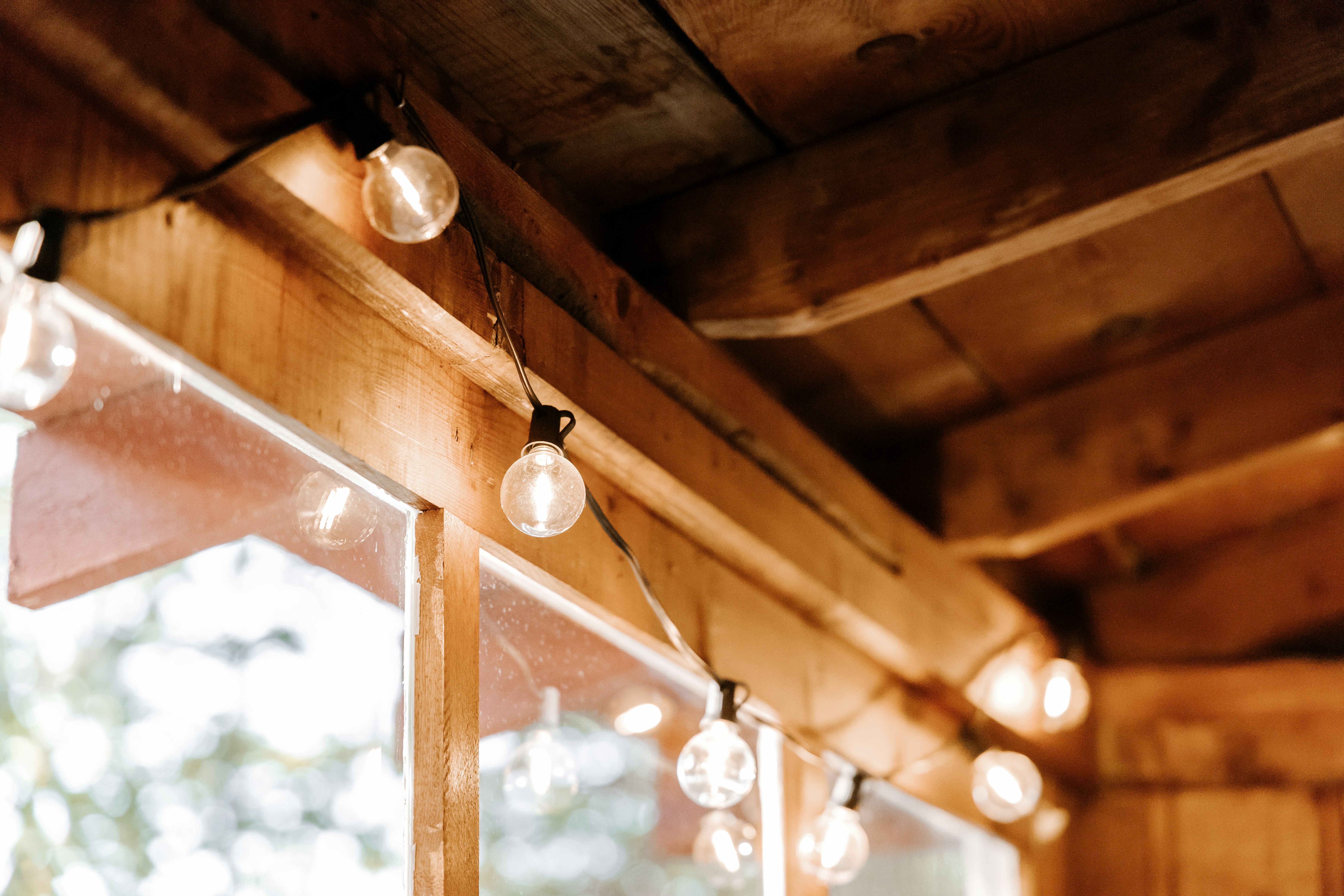 String lights illuminate the rustic wooden interior, creating a warm and inviting atmosphere in a cabin setting.