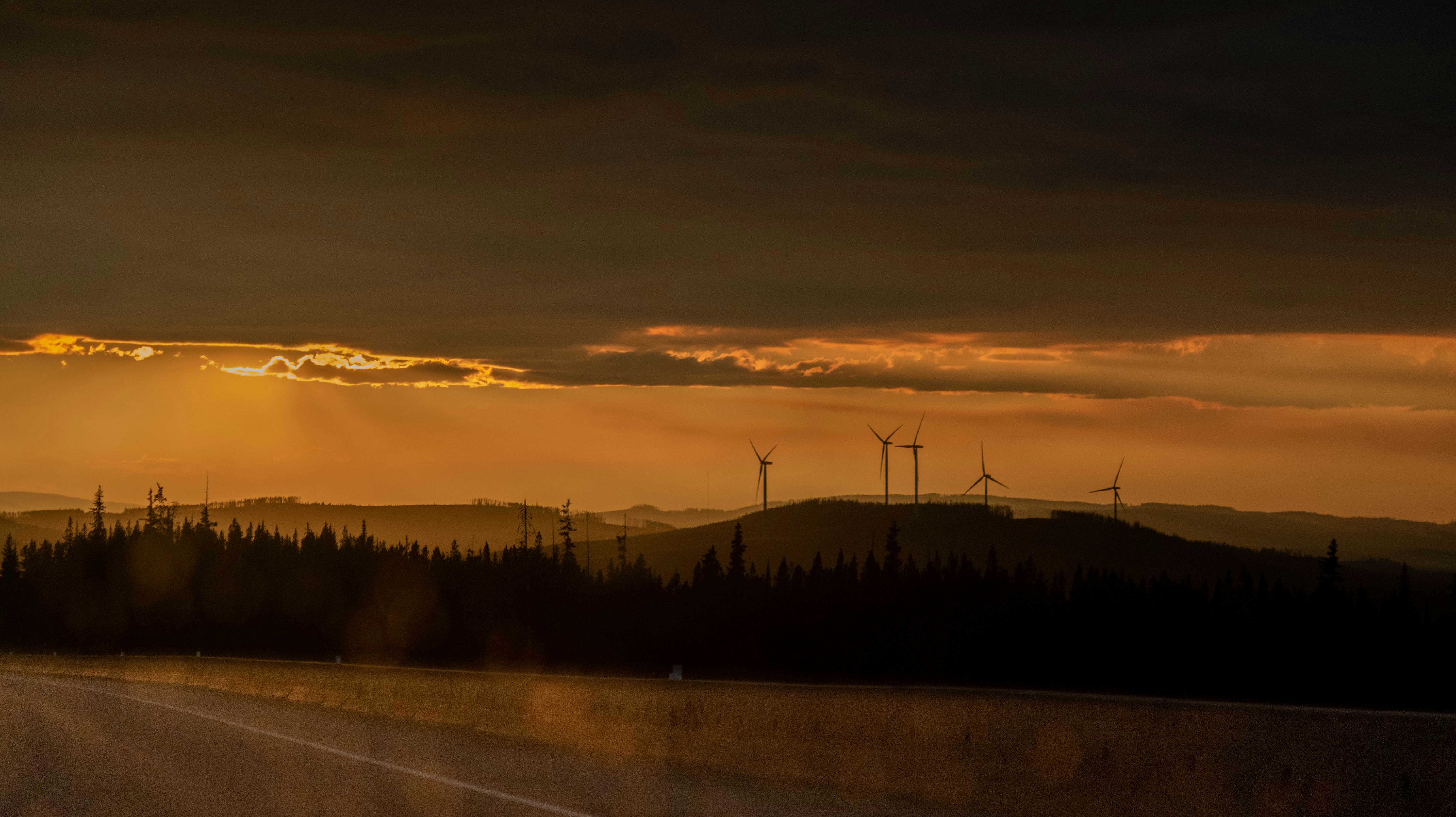 Distant Wind Turbines at Sunset Over a Quiet Highway