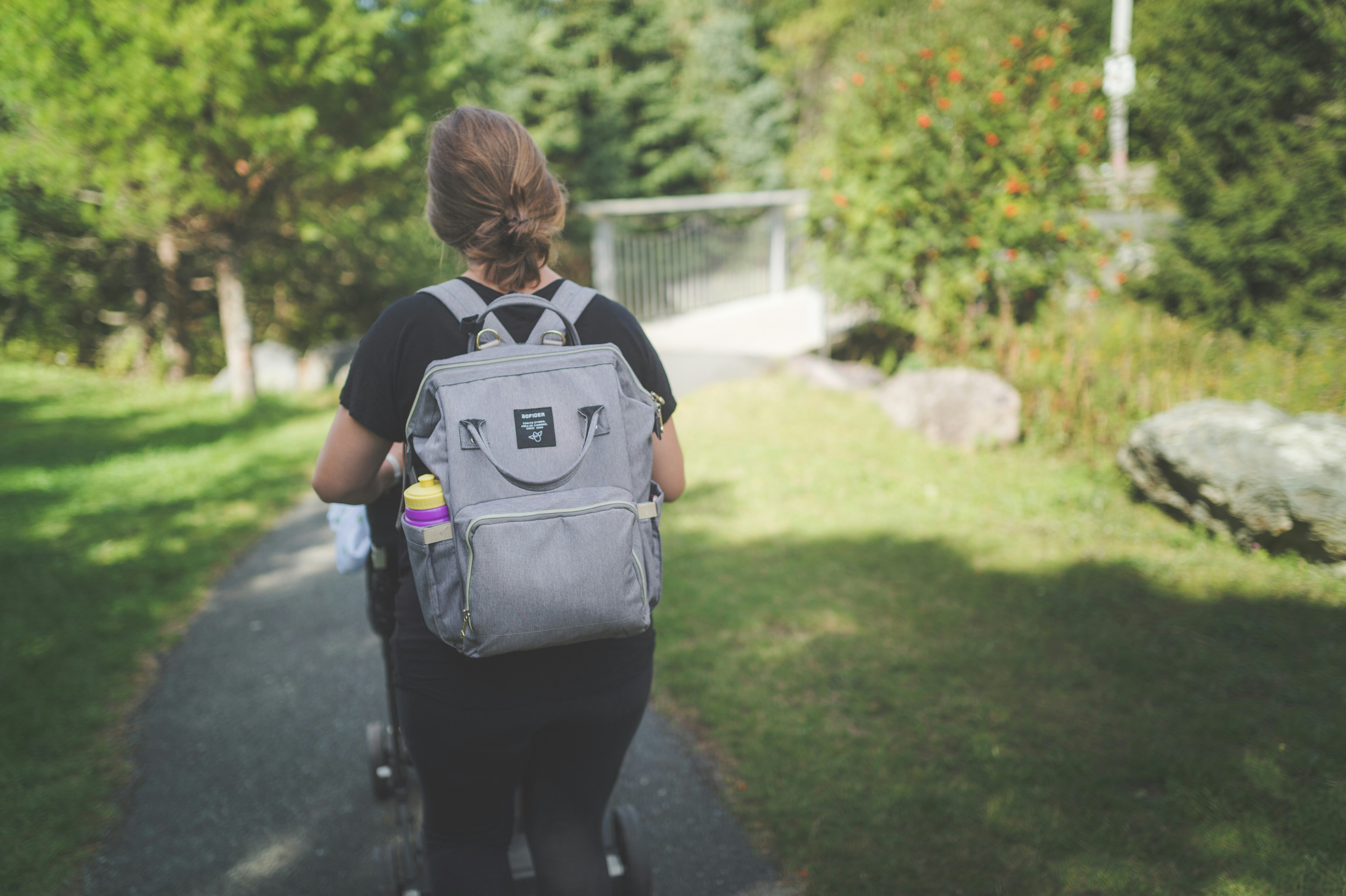 Woman in black and white backpack walking on sidewalk during daytime ...