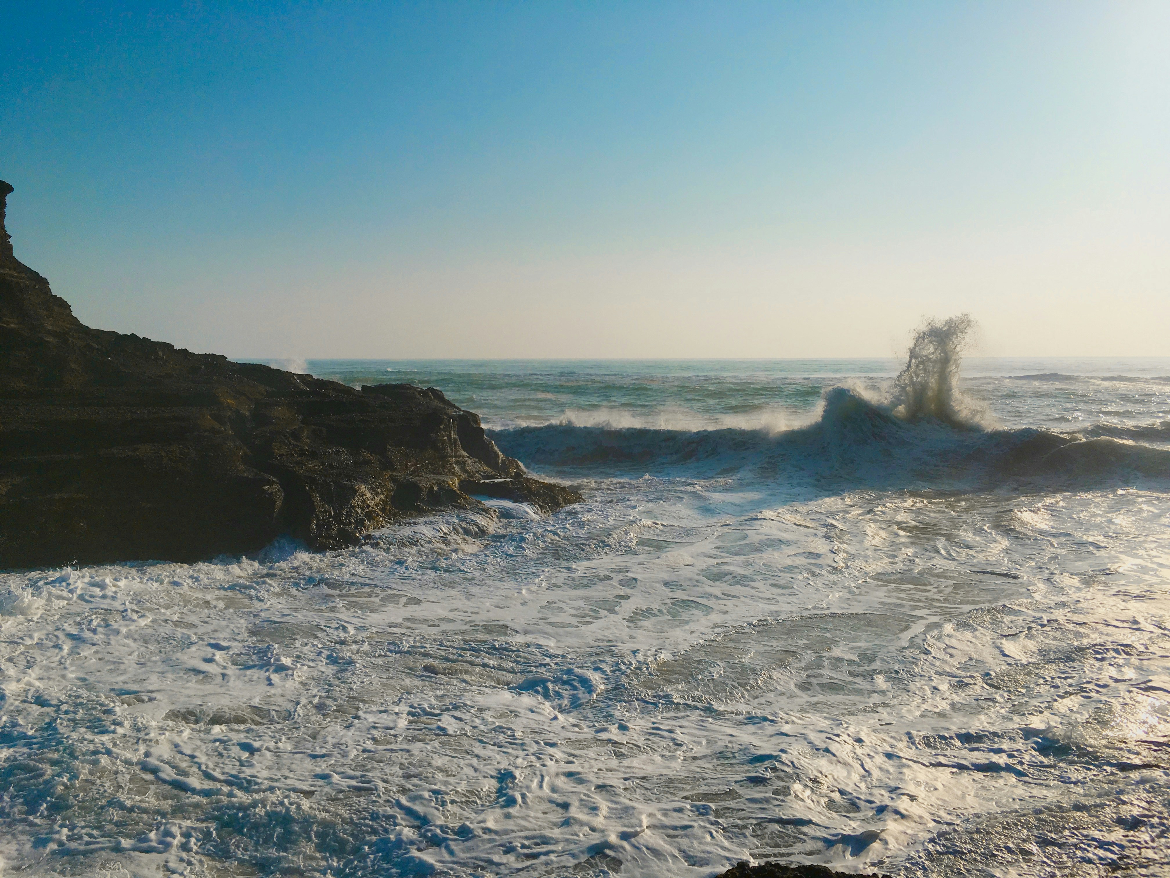 Coastal Crest: Sunlit Breakers Over a Rocky Shore