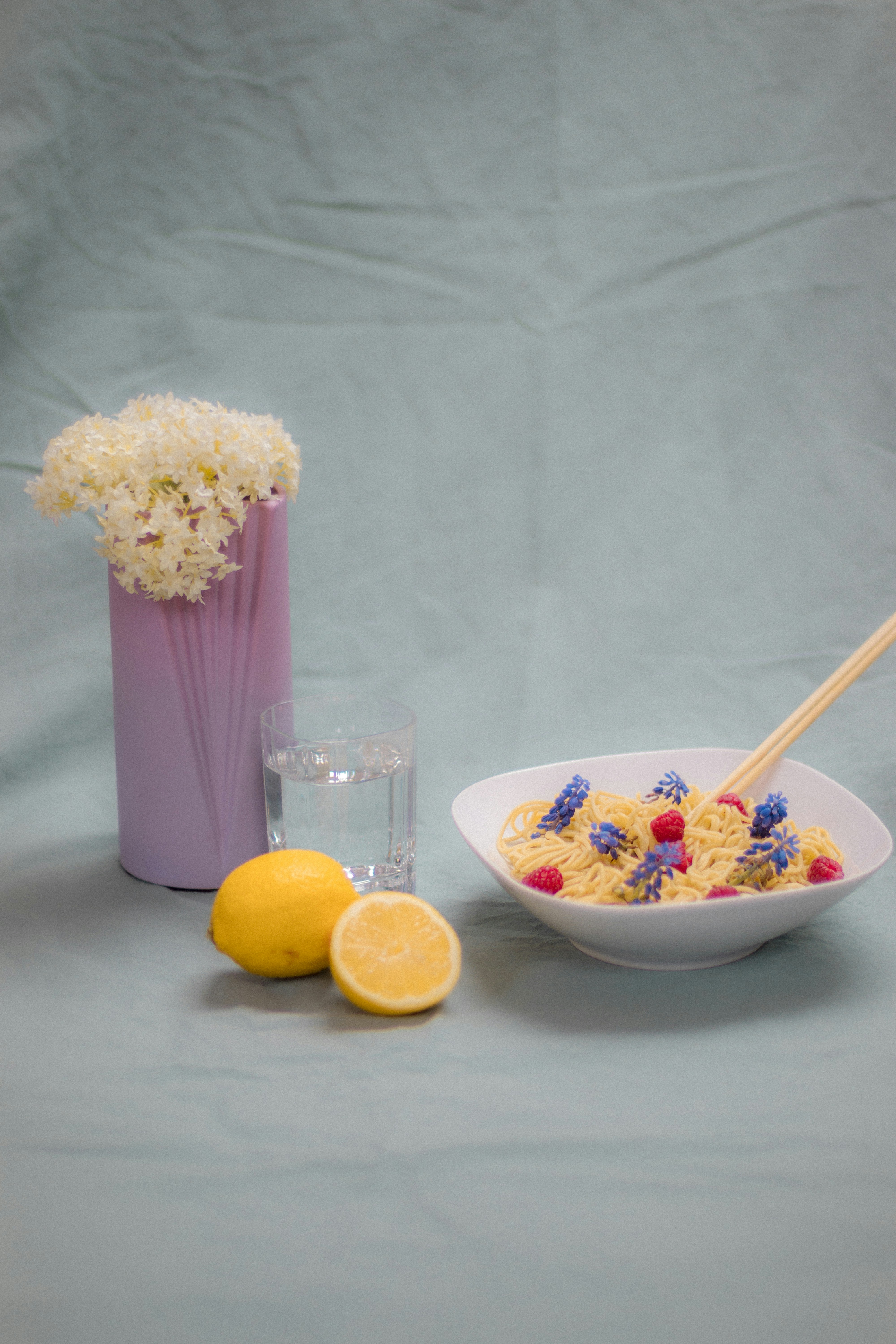 Pastel Still Life: Lemons, Pasta, and Lilac Vase on a Soft Blue Backdrop
