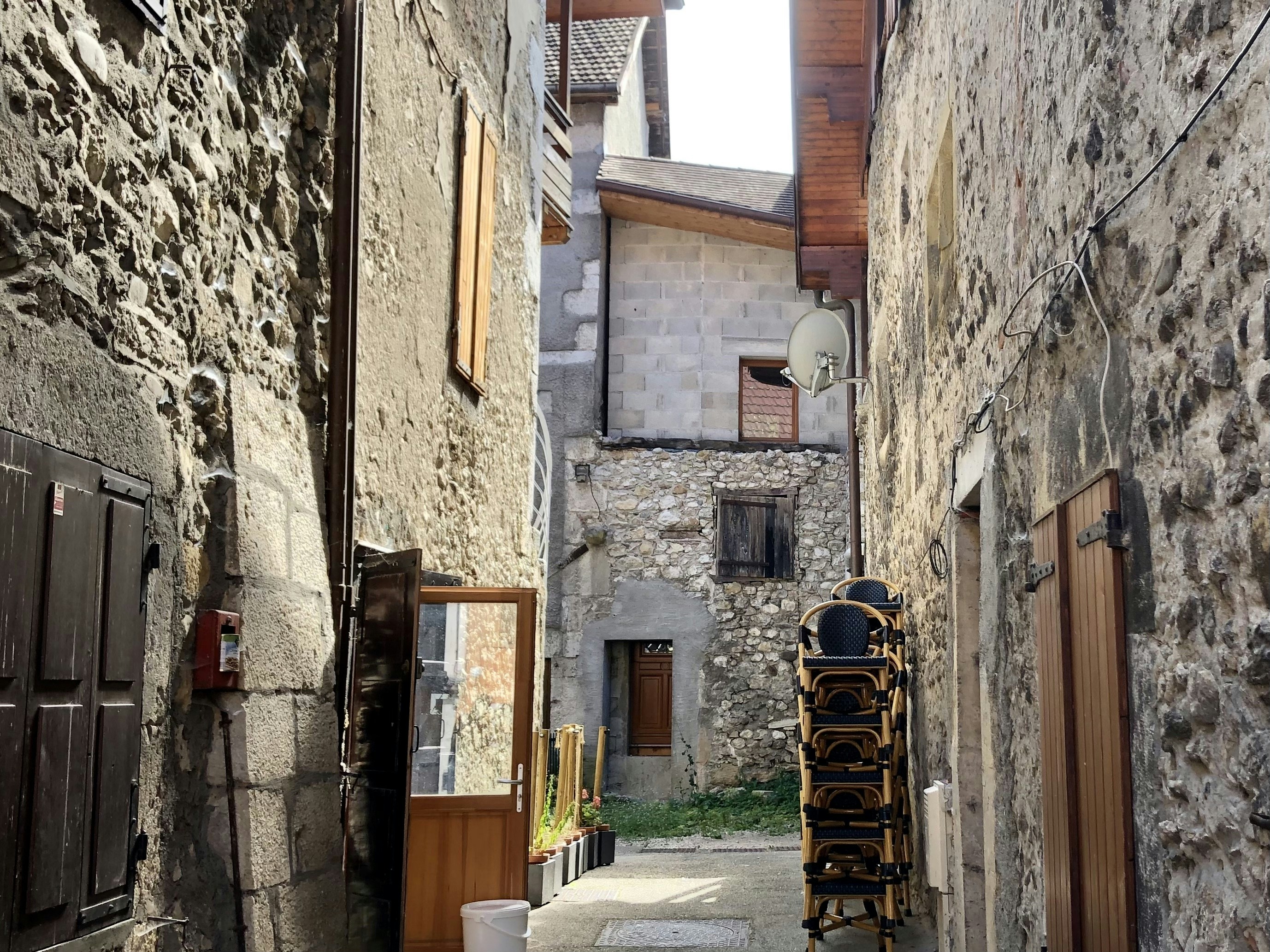 A narrow alley way with a chair in between two buildings photo – Free ...