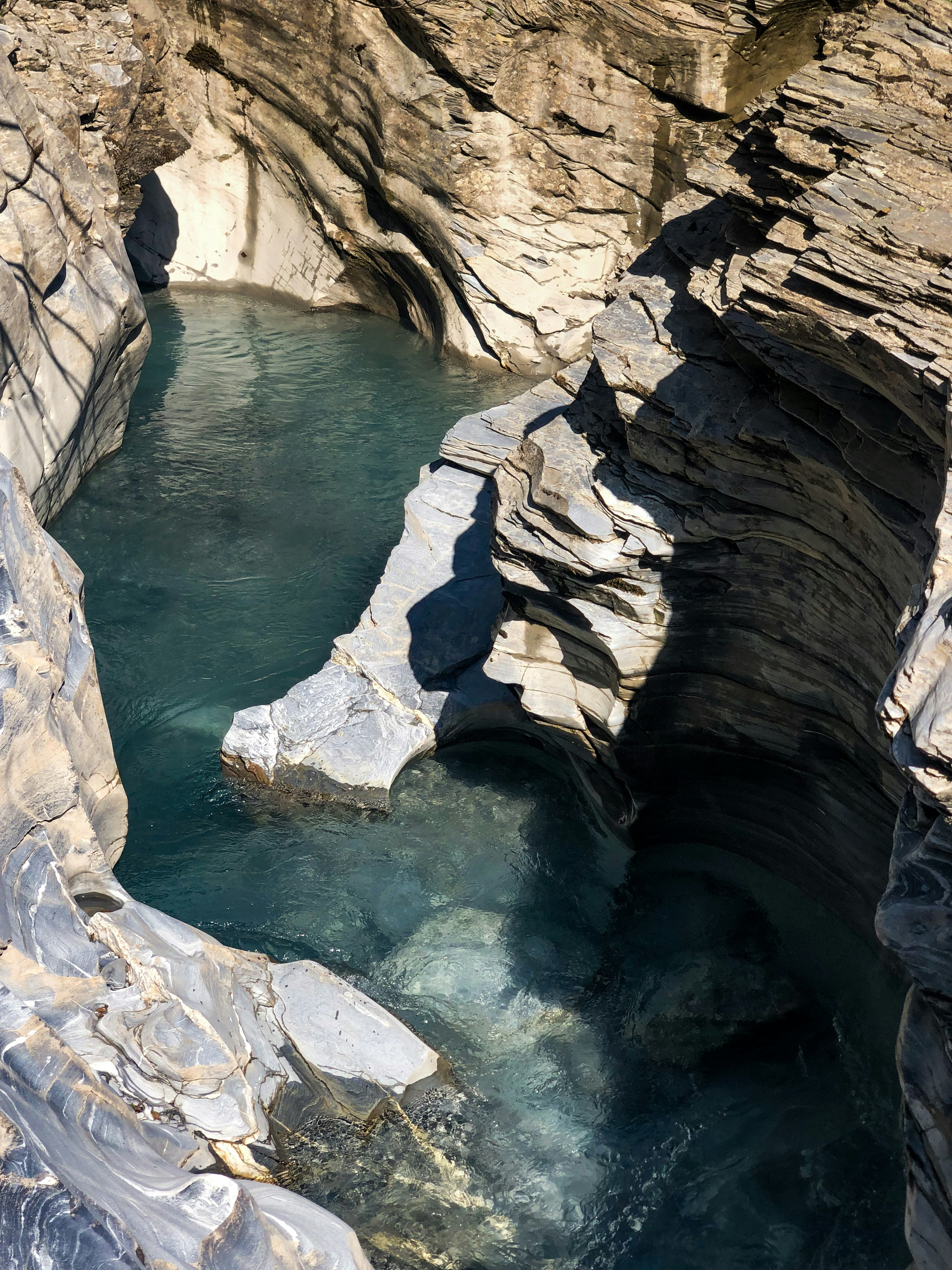 A body of water surrounded by large rocks photo – Free Trutg dil flem ...