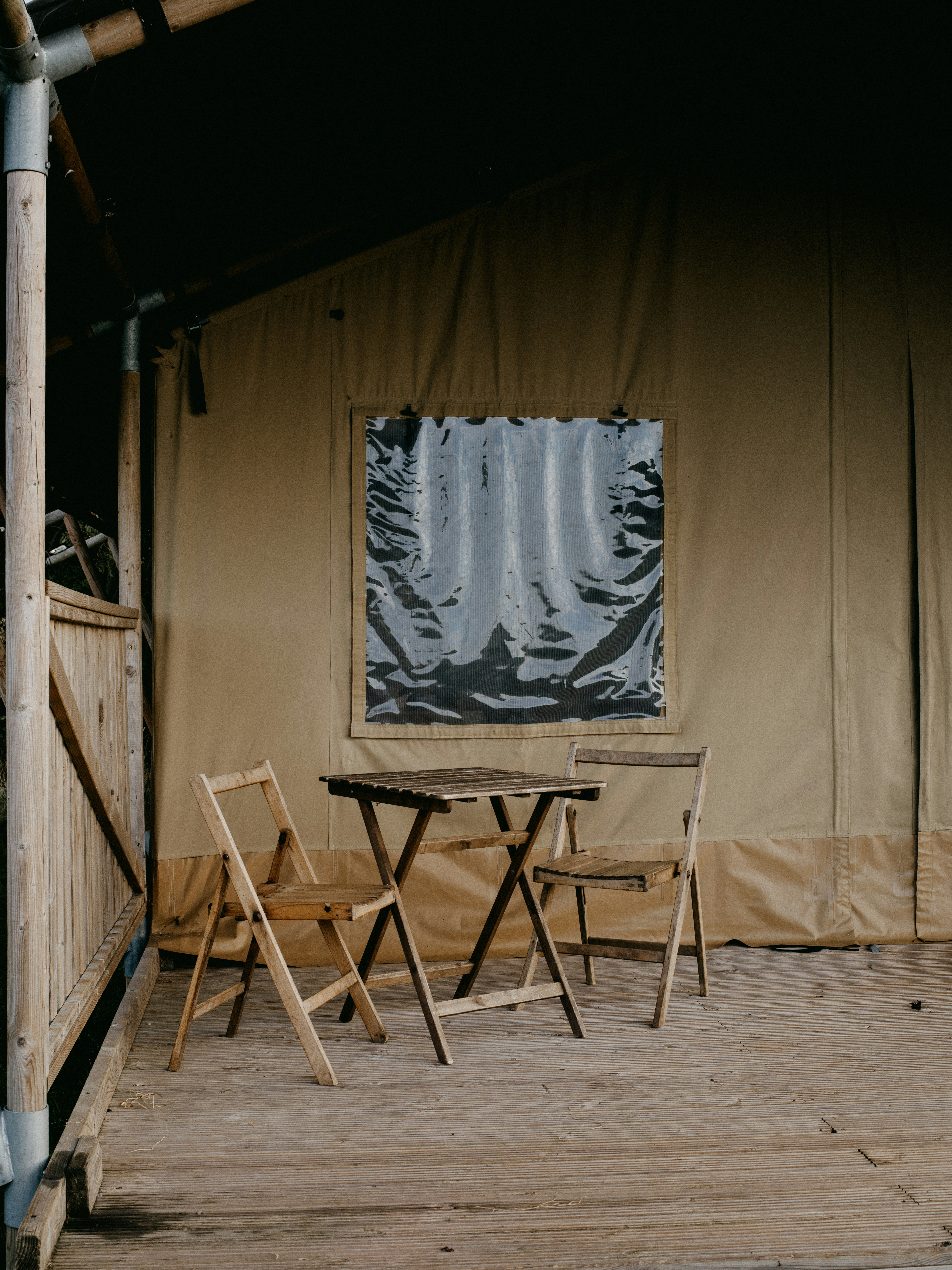 Under Canvas on a Quiet Deck: Folding Table and Chairs by a Wrinkled Window