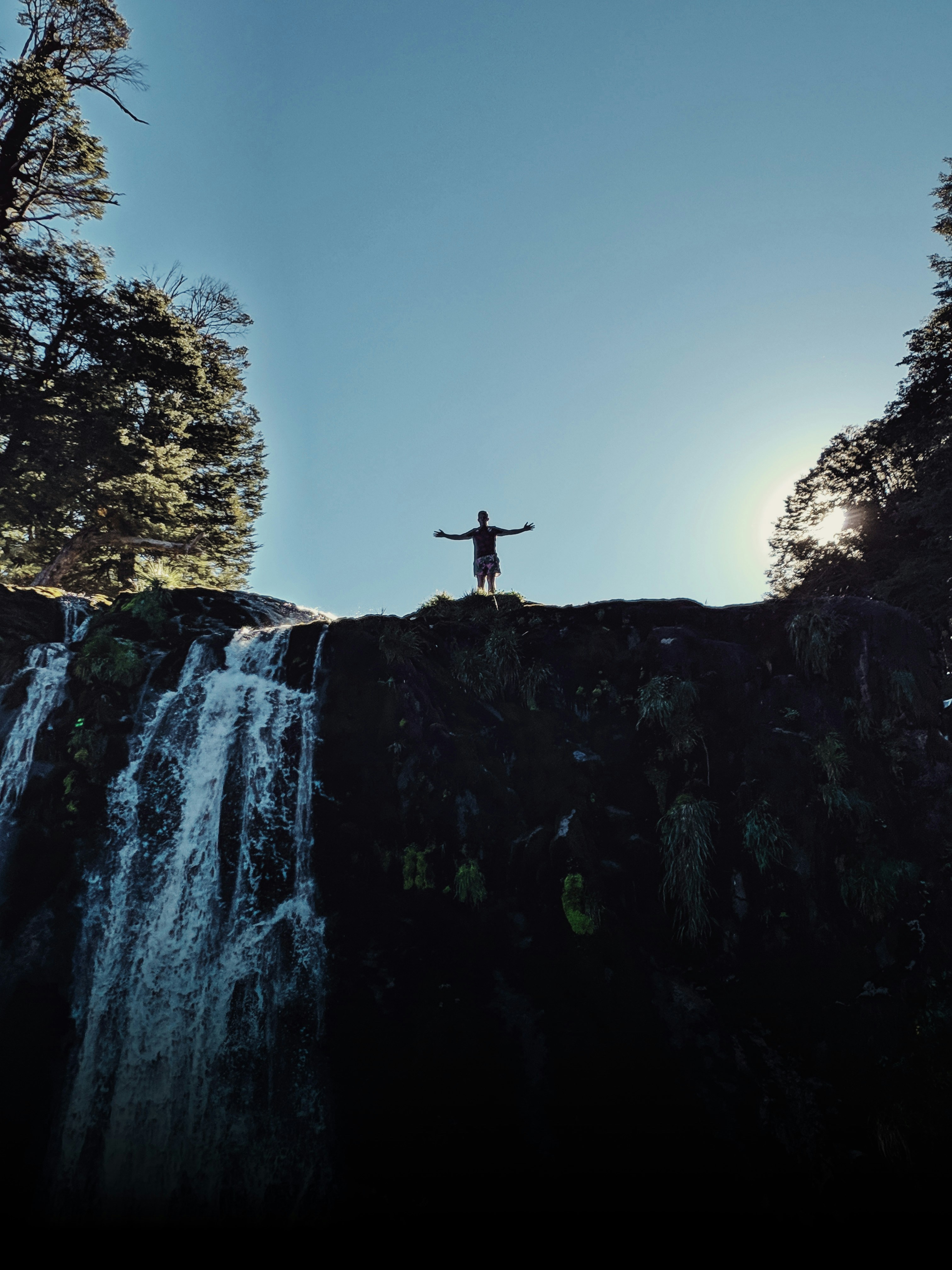 A person standing on top of a waterfall photo – Free Blue Image on Unsplash