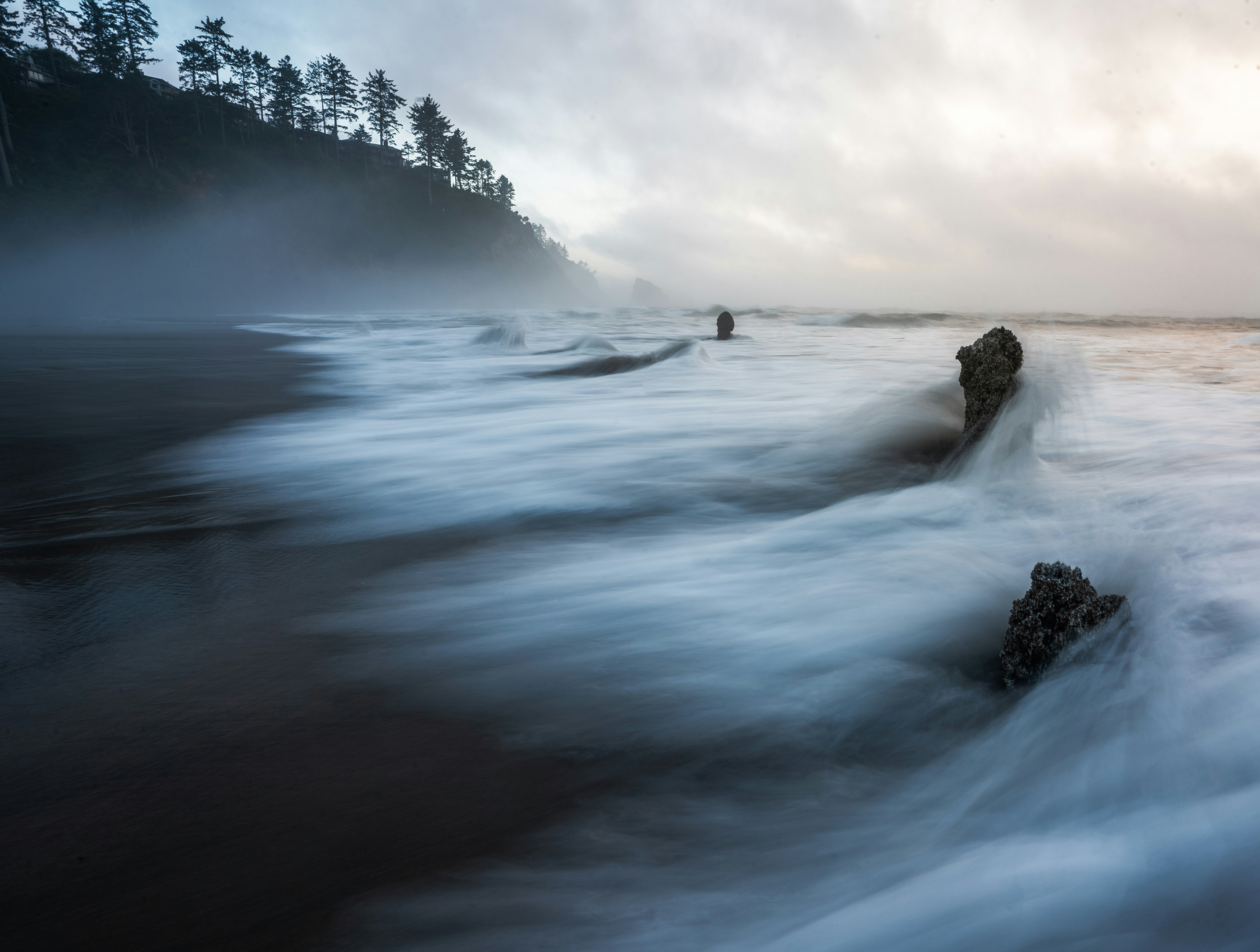 A man standing on top of a wave covered beach photo – Free Beach Image ...