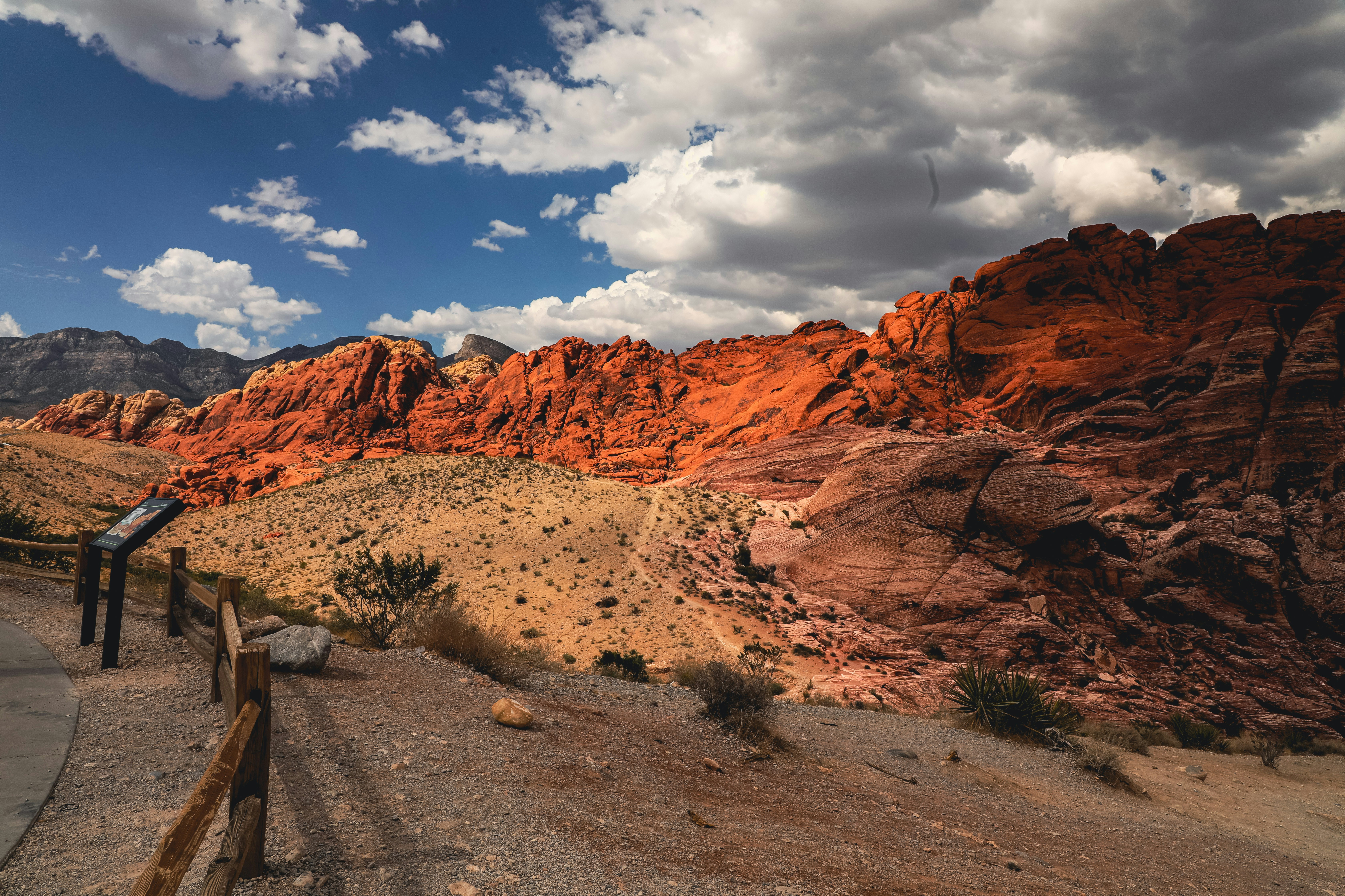 Vast desert landscape with striking red rock formations under a partly cloudy sky.
