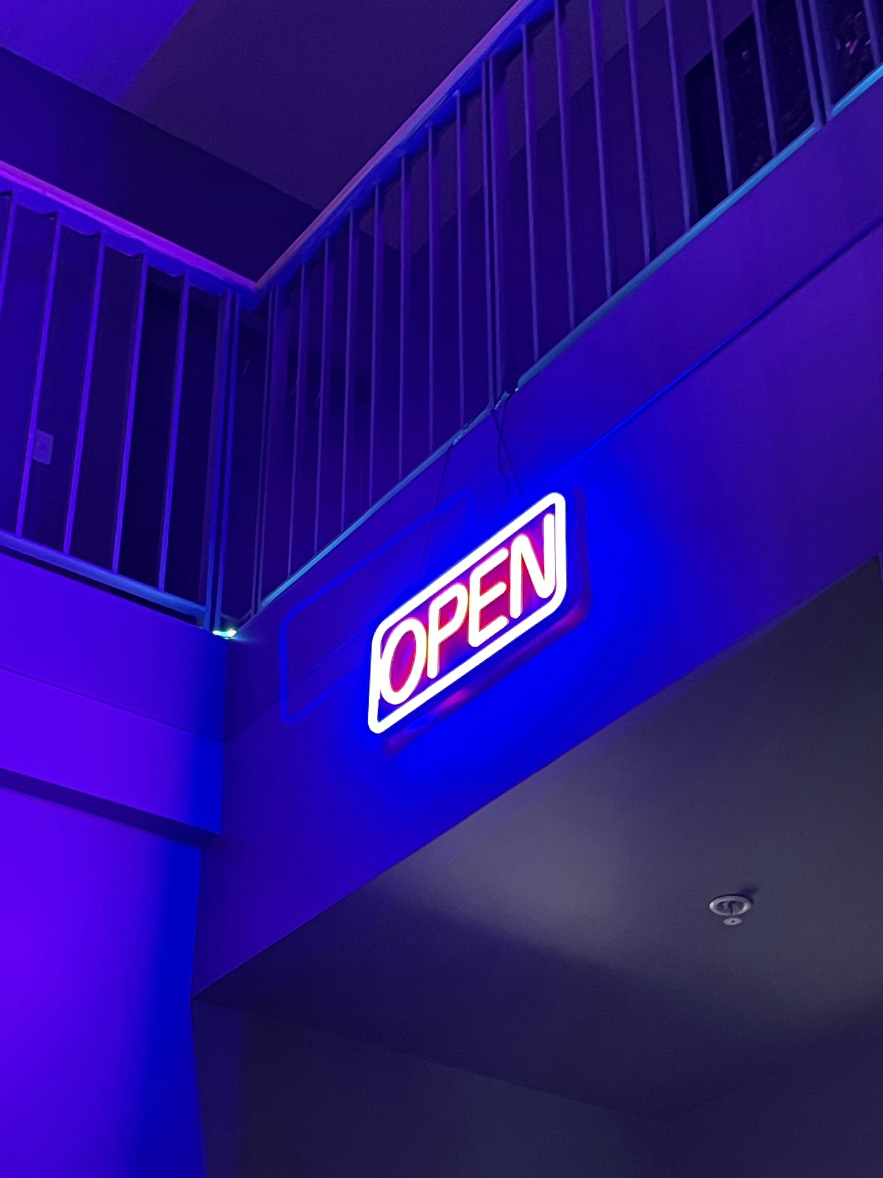 A neon sign that reads open above a stairwell photo – Free Blue Image ...