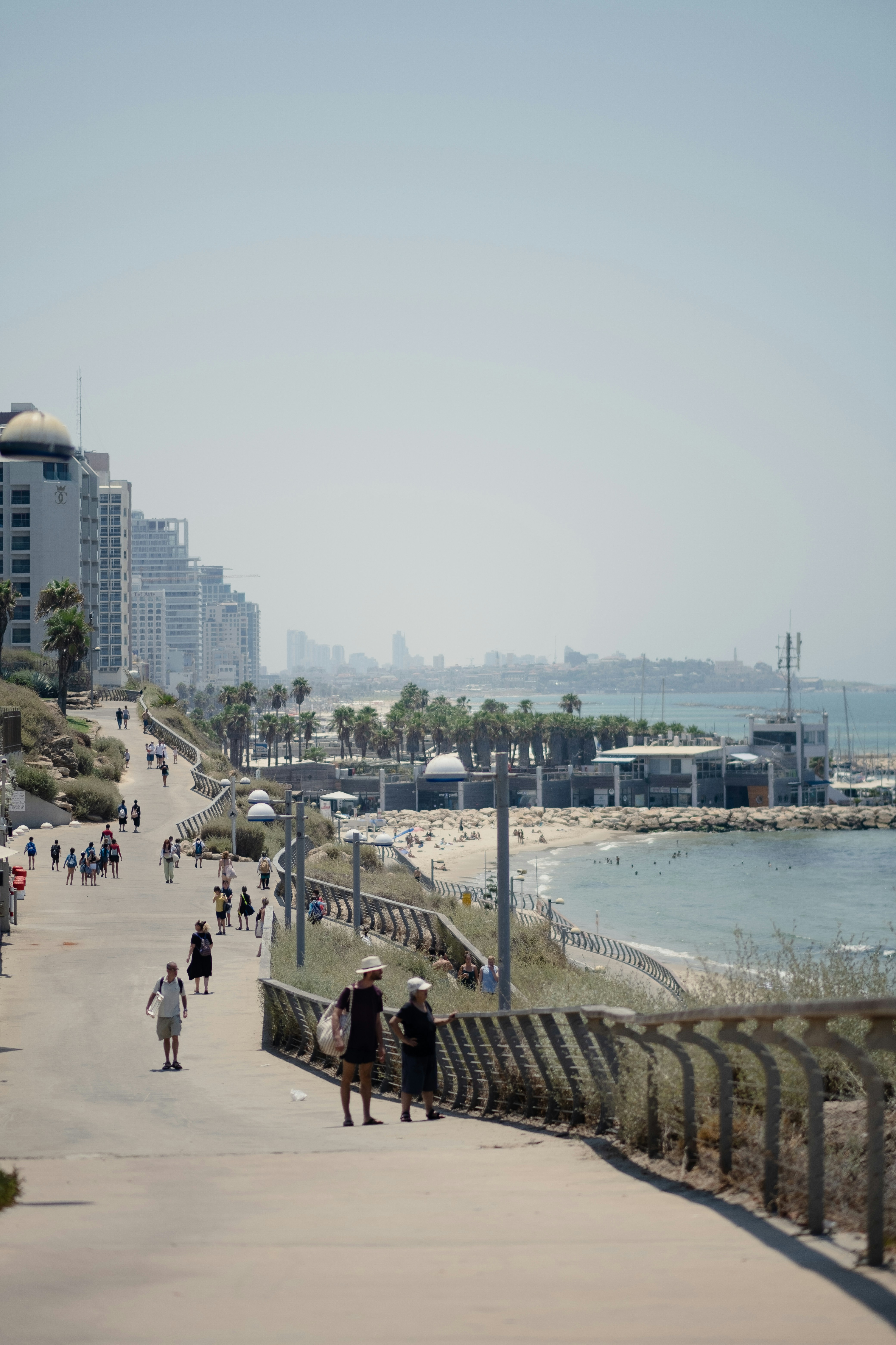 A group of people walking down a sidewalk next to the ocean photo ...