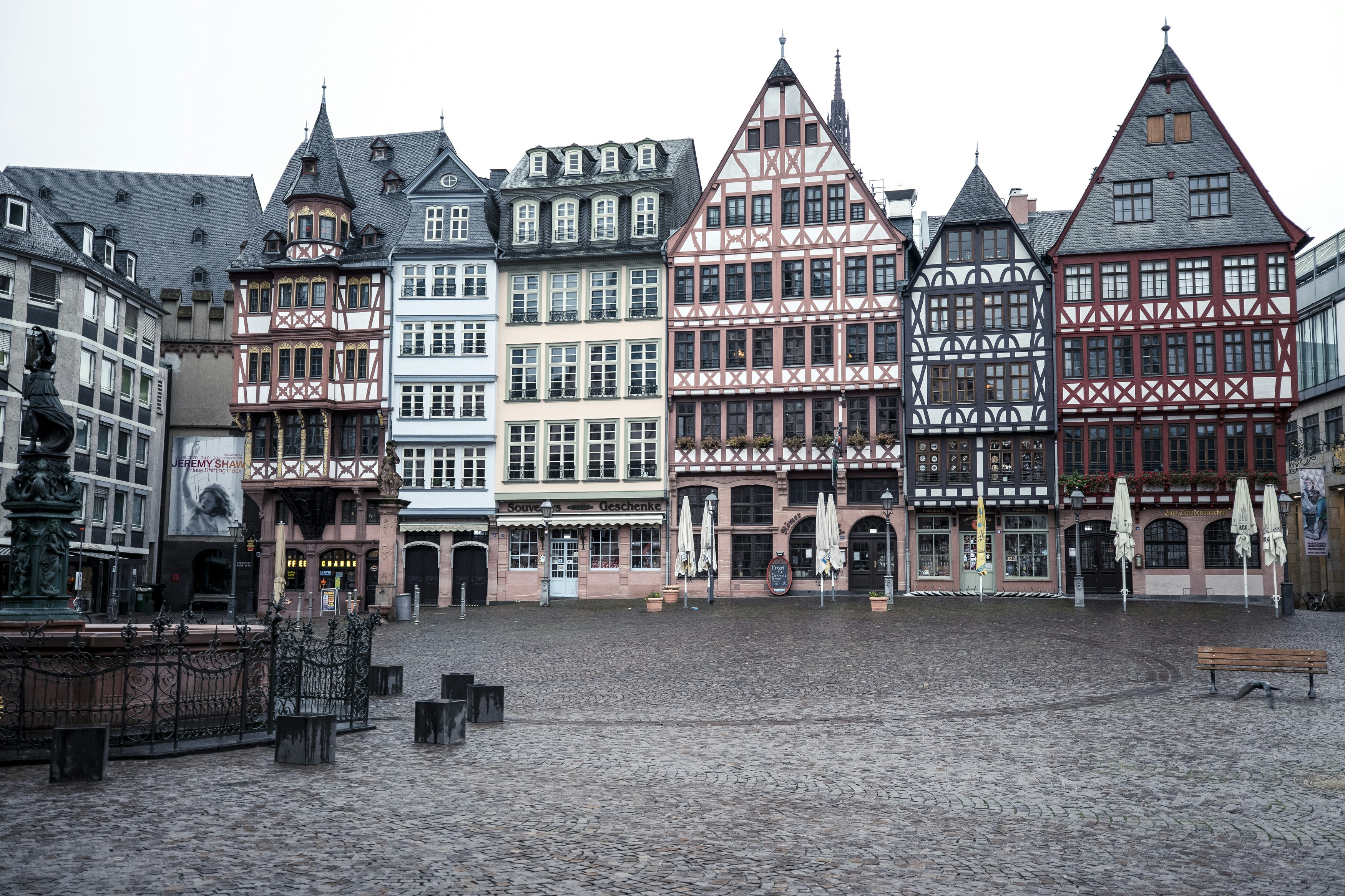 Colorful timber-framed buildings line a cobblestone plaza under an overcast sky.