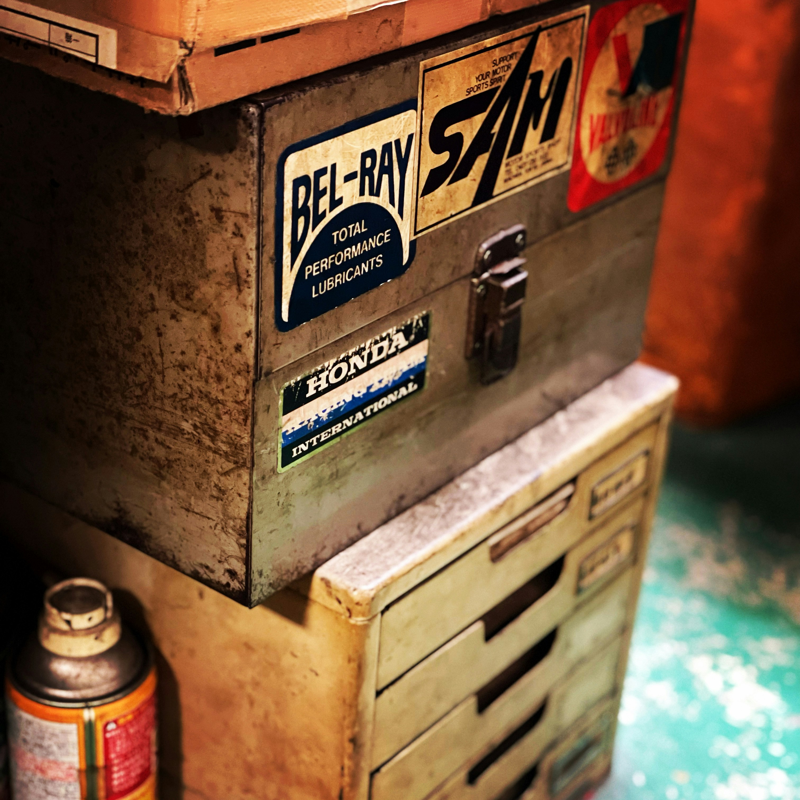A weathered toolbox adorned with vintage stickers, showcasing a blend of nostalgia and craftsmanship. The scene captures the essence of a workshop filled with history.