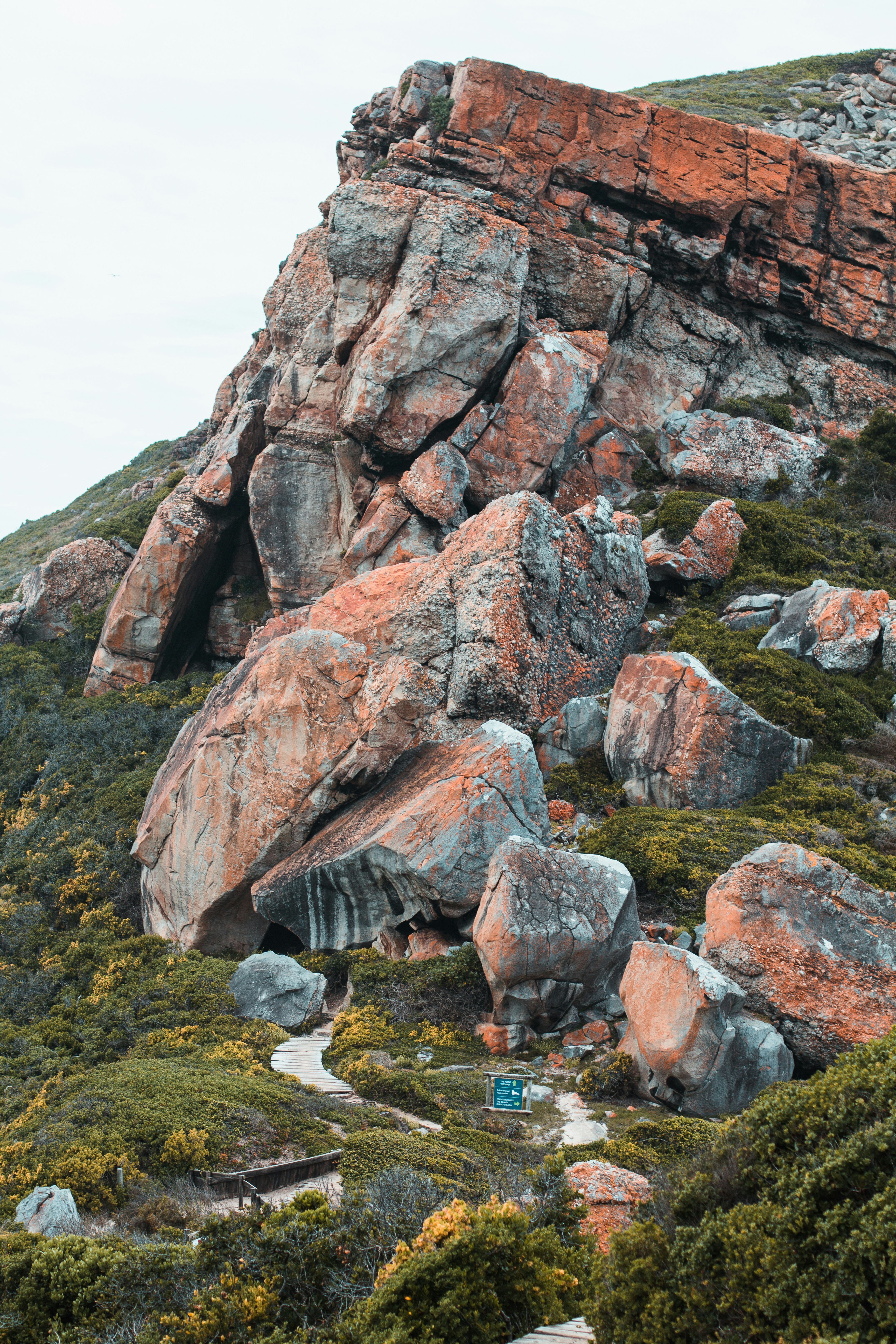 Massive, textured boulders rise from a lush, green landscape, with a winding path leading through the natural formations.