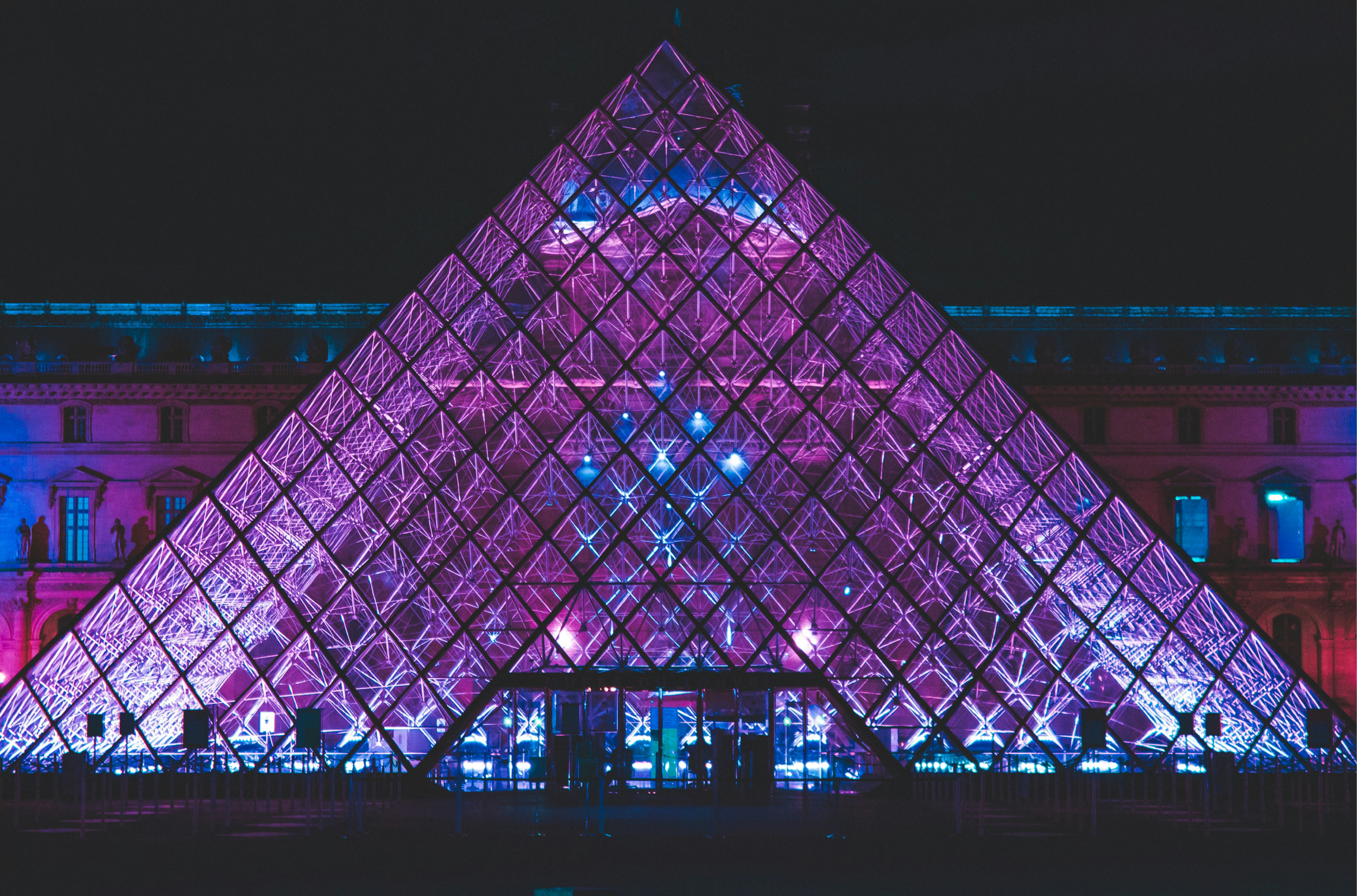 A large pyramid shaped building lit up at night photo – Free Paris ...