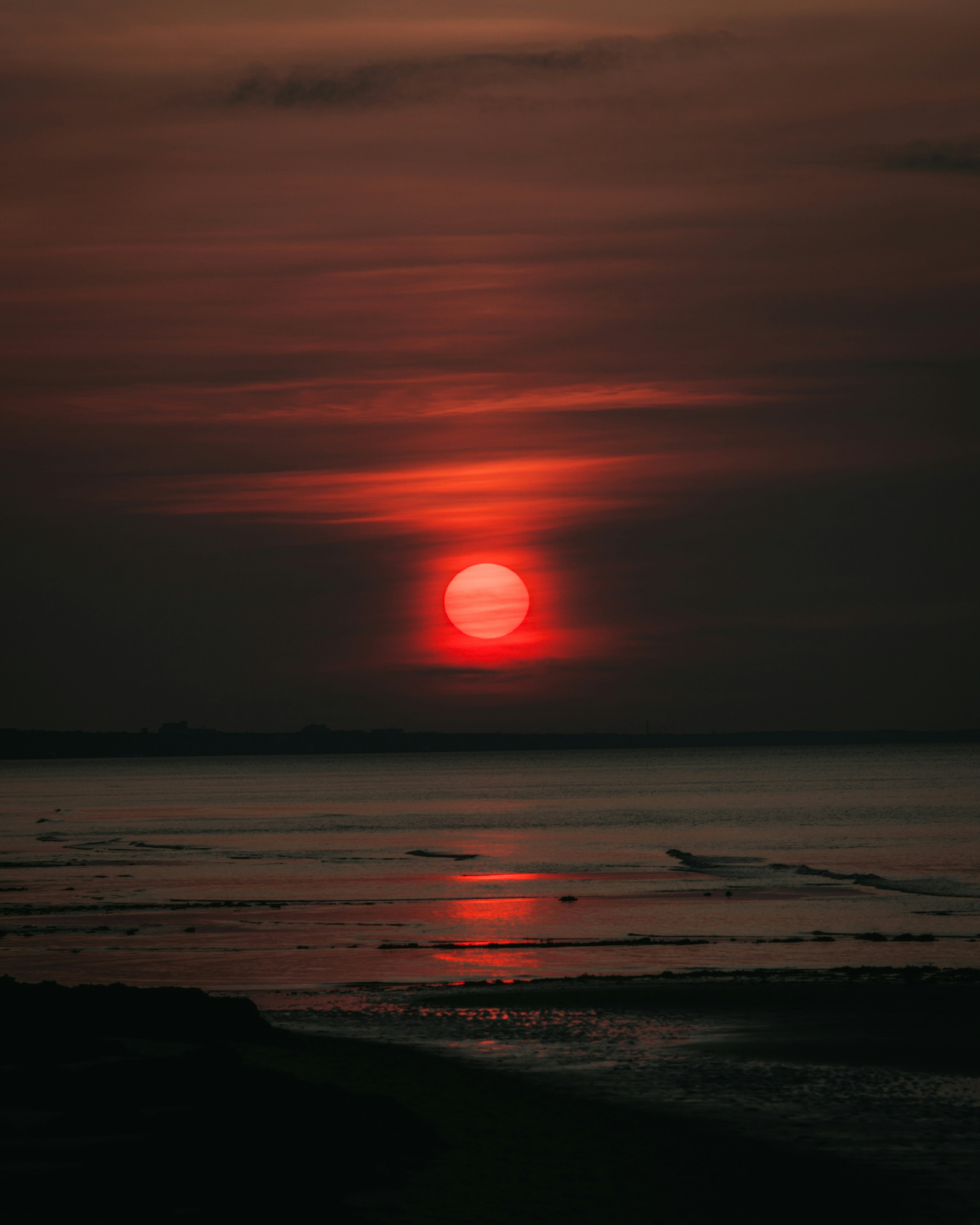 Crimson Sun on a Quiet Shore: Dusk Reflections