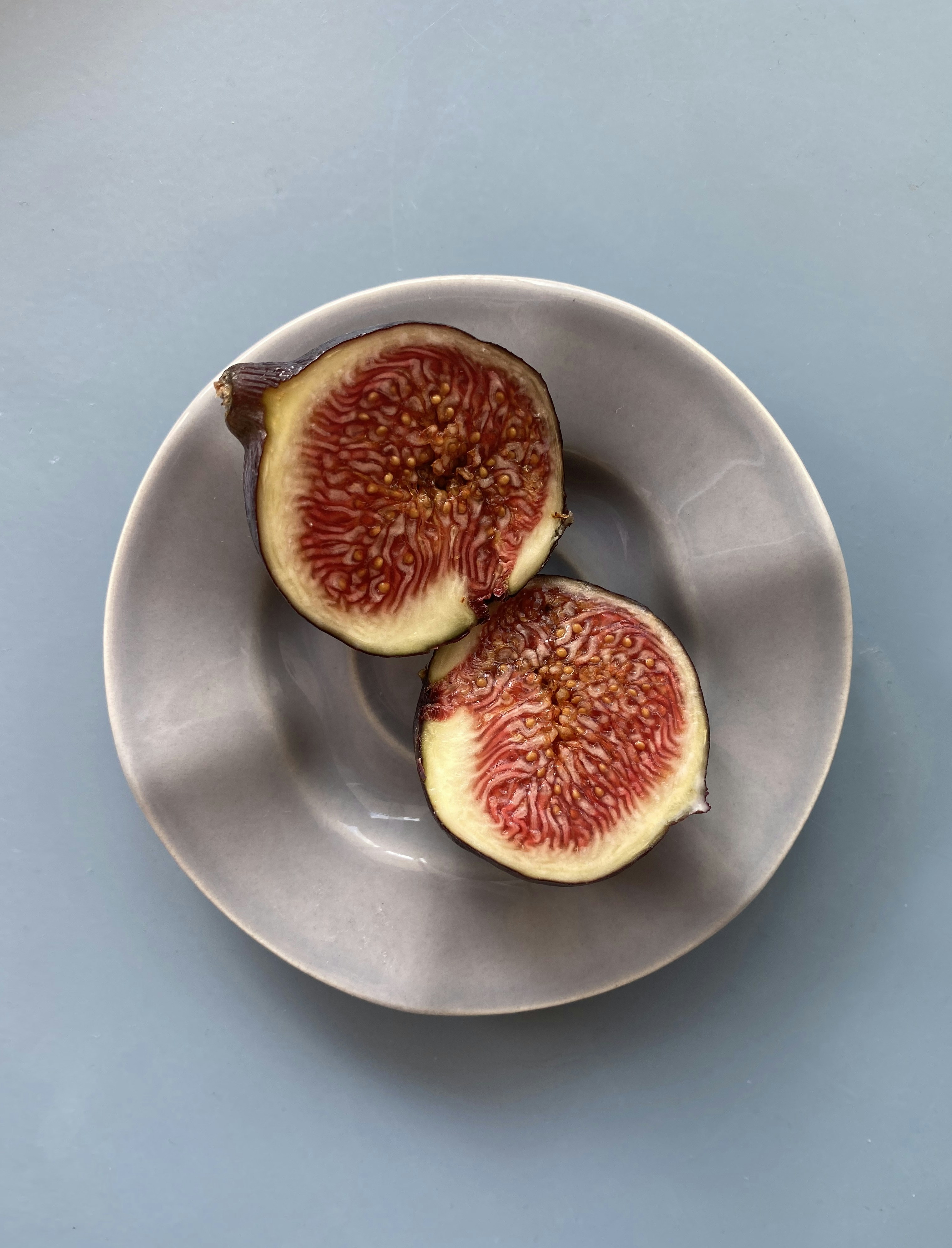 Two figs on a plate on a blue table photo – Free Fruit Image on Unsplash