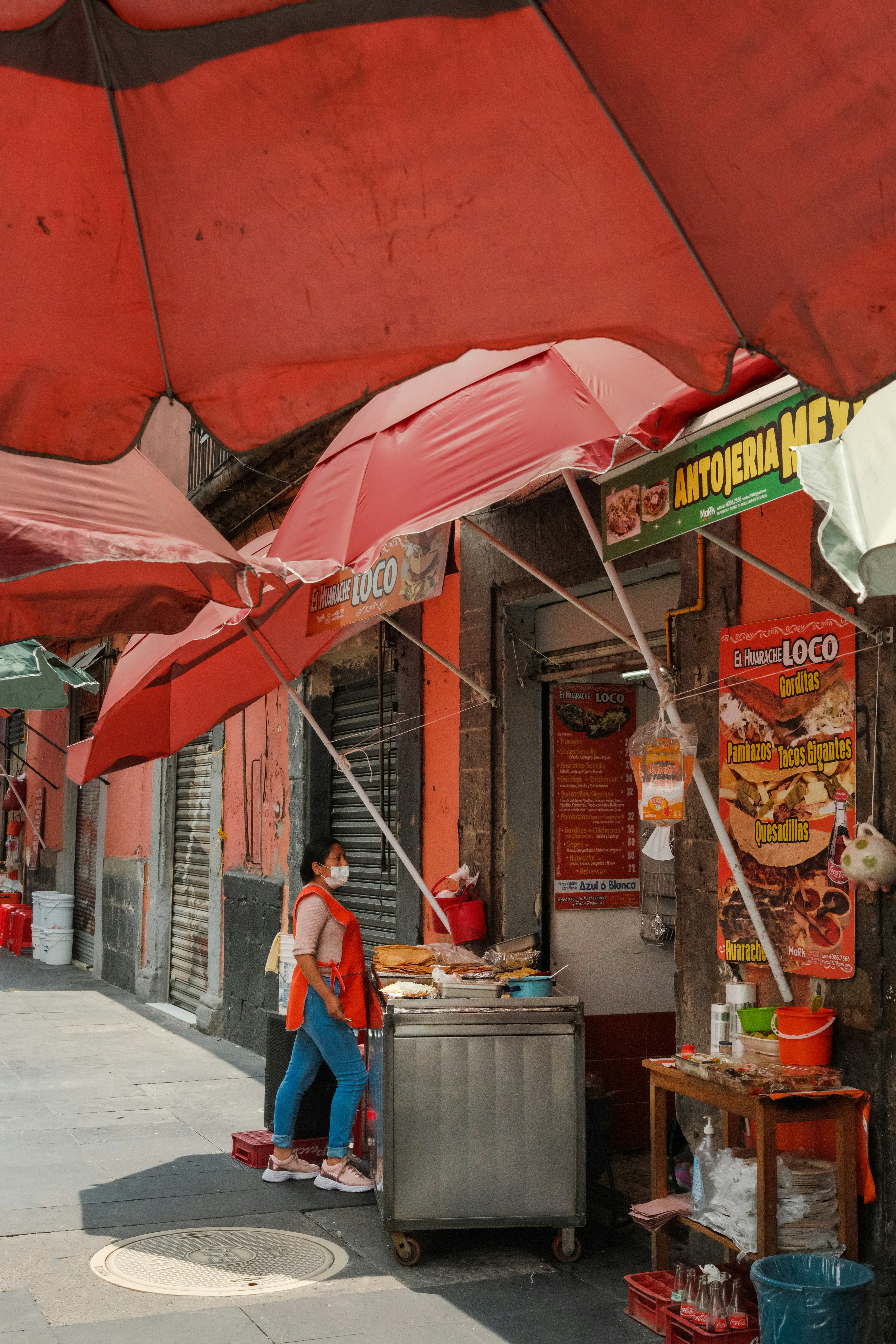 Masked Vendor Under Coral Awnings by a Street Cart