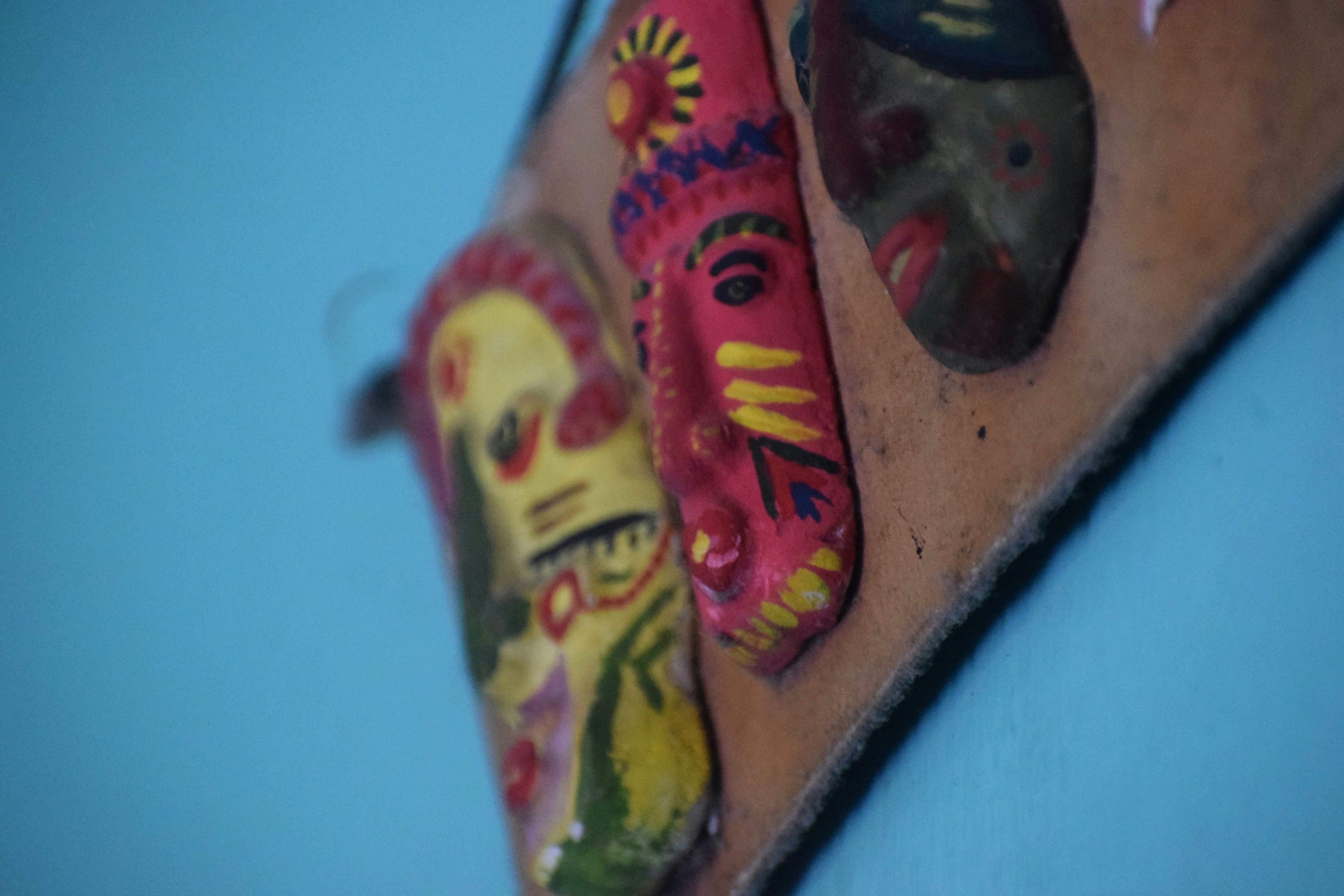 Vividly painted masks mounted on a textured background, showcasing intricate designs and cultural significance.