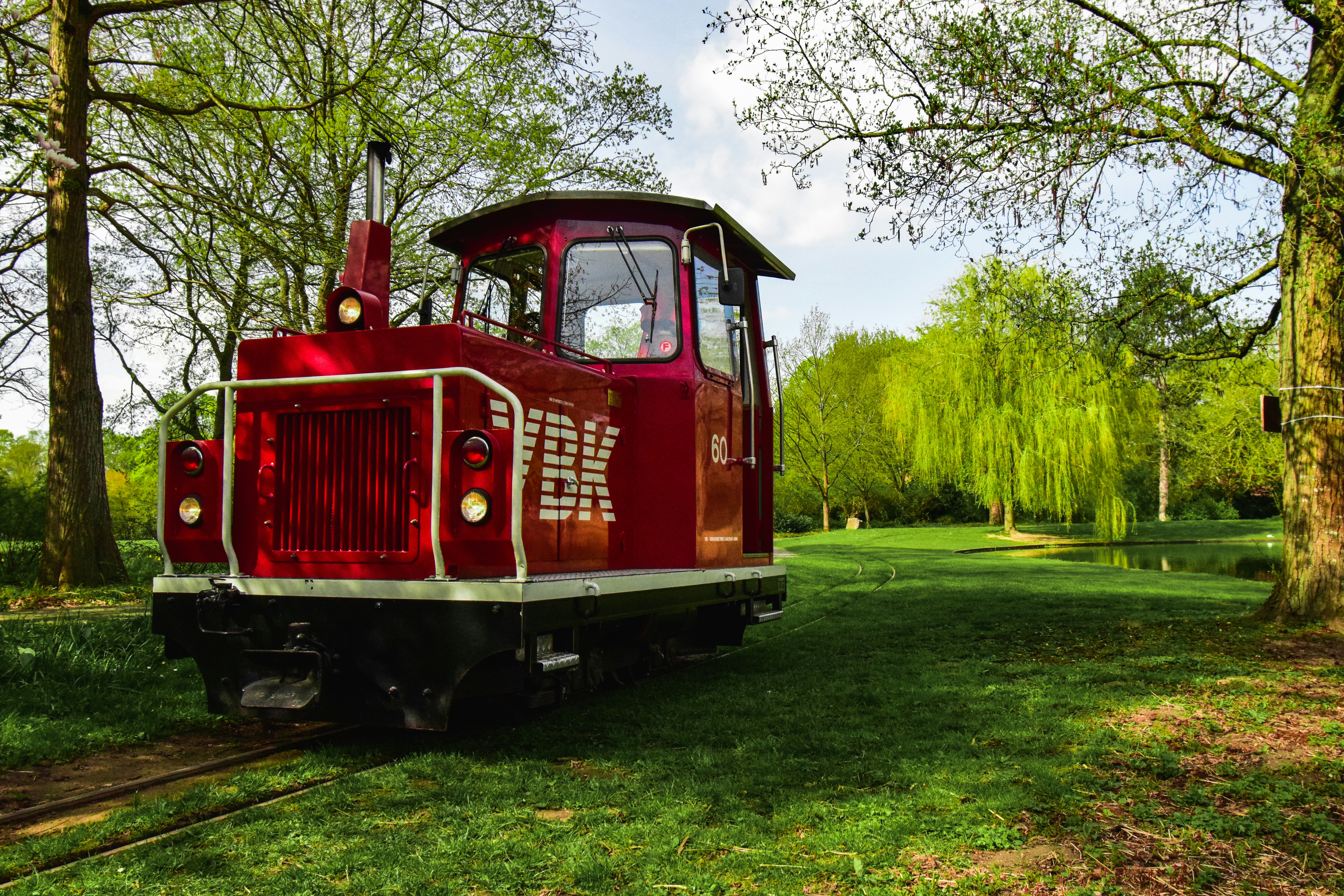 A red train car sitting in the middle of a park photo – Free Wallpaper ...