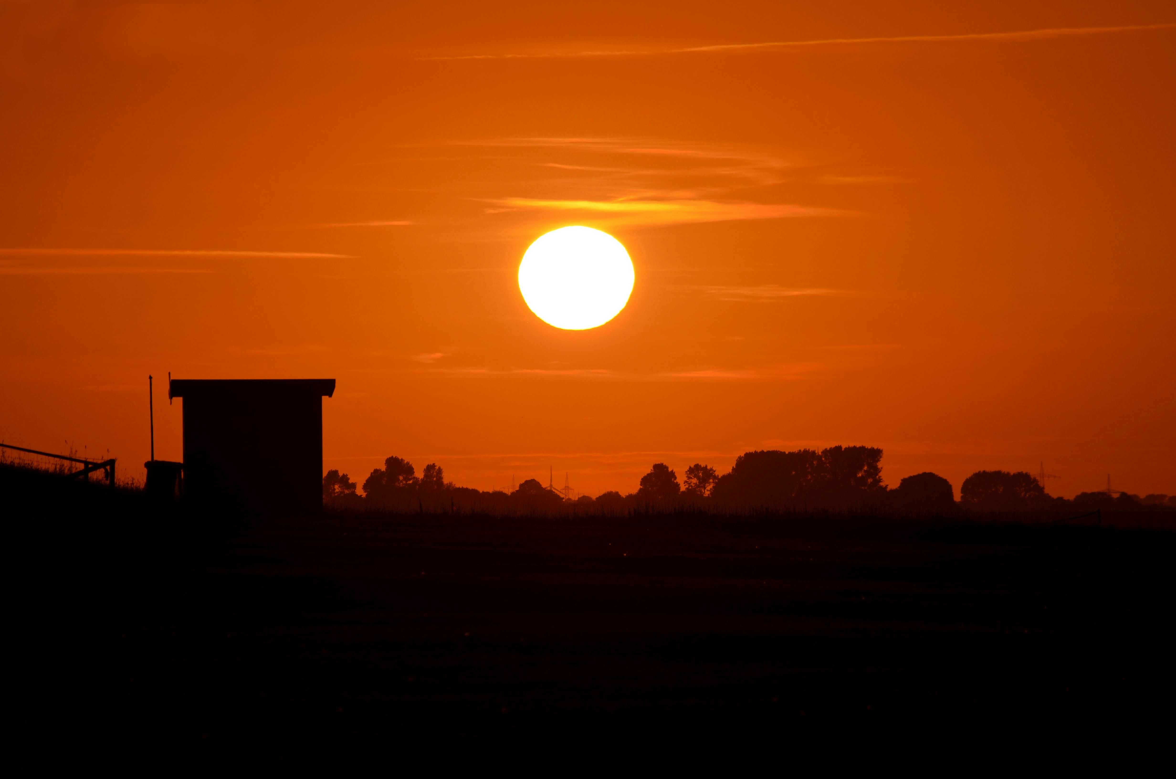the sun is setting over a farm with a silo in the foreground